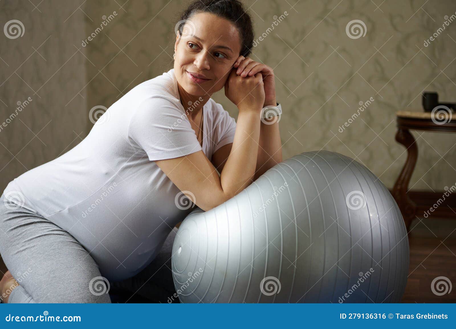 Ethnic Adult Pregnant Woman Leaning On A Fit Ball Smiling Looking Away