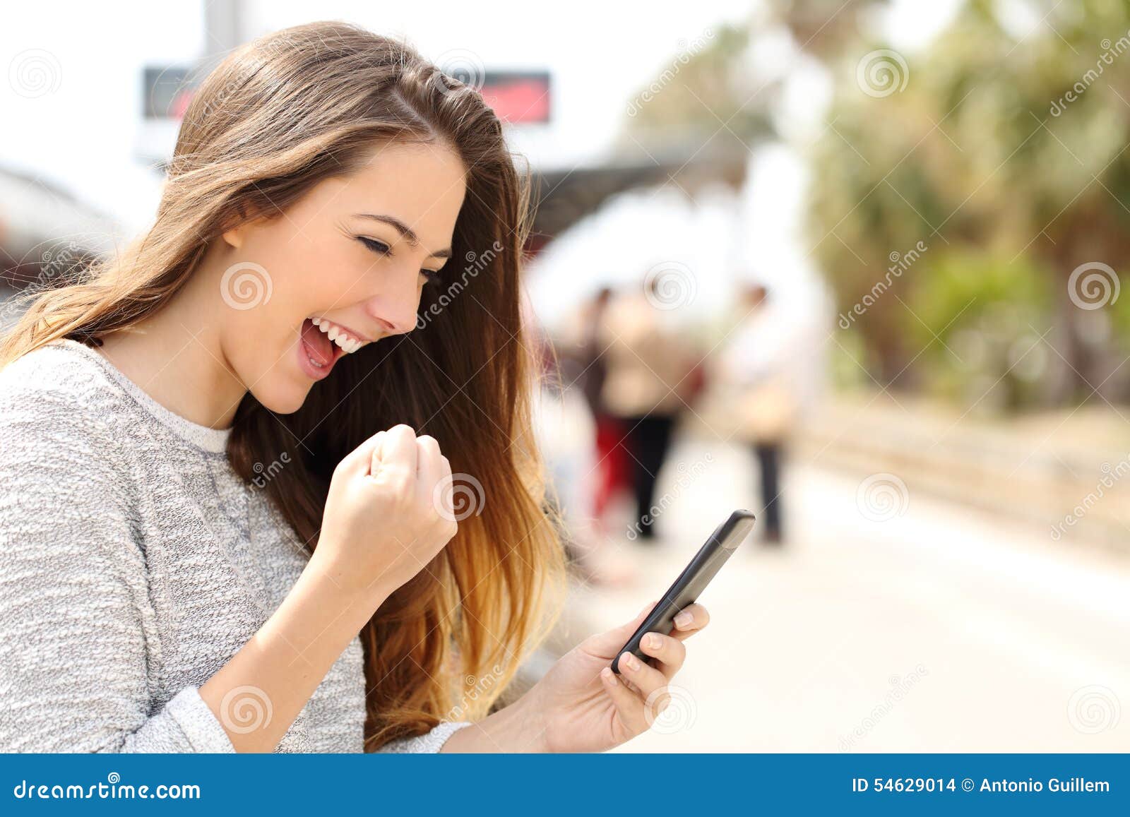 Euphoric Woman Watching Her Smart Phone in a Train Station Stock Photo ...