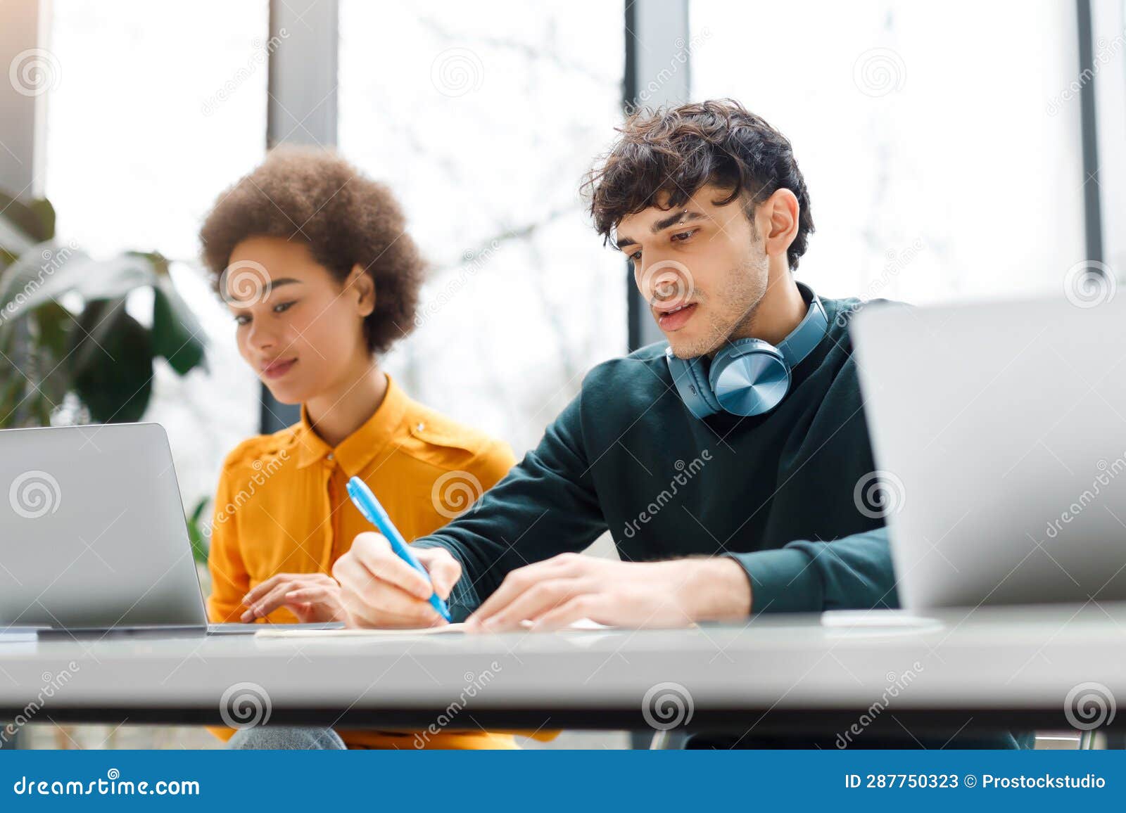 European Student Guy Taking Notes in Copybook, Doing Homework, Studying ...