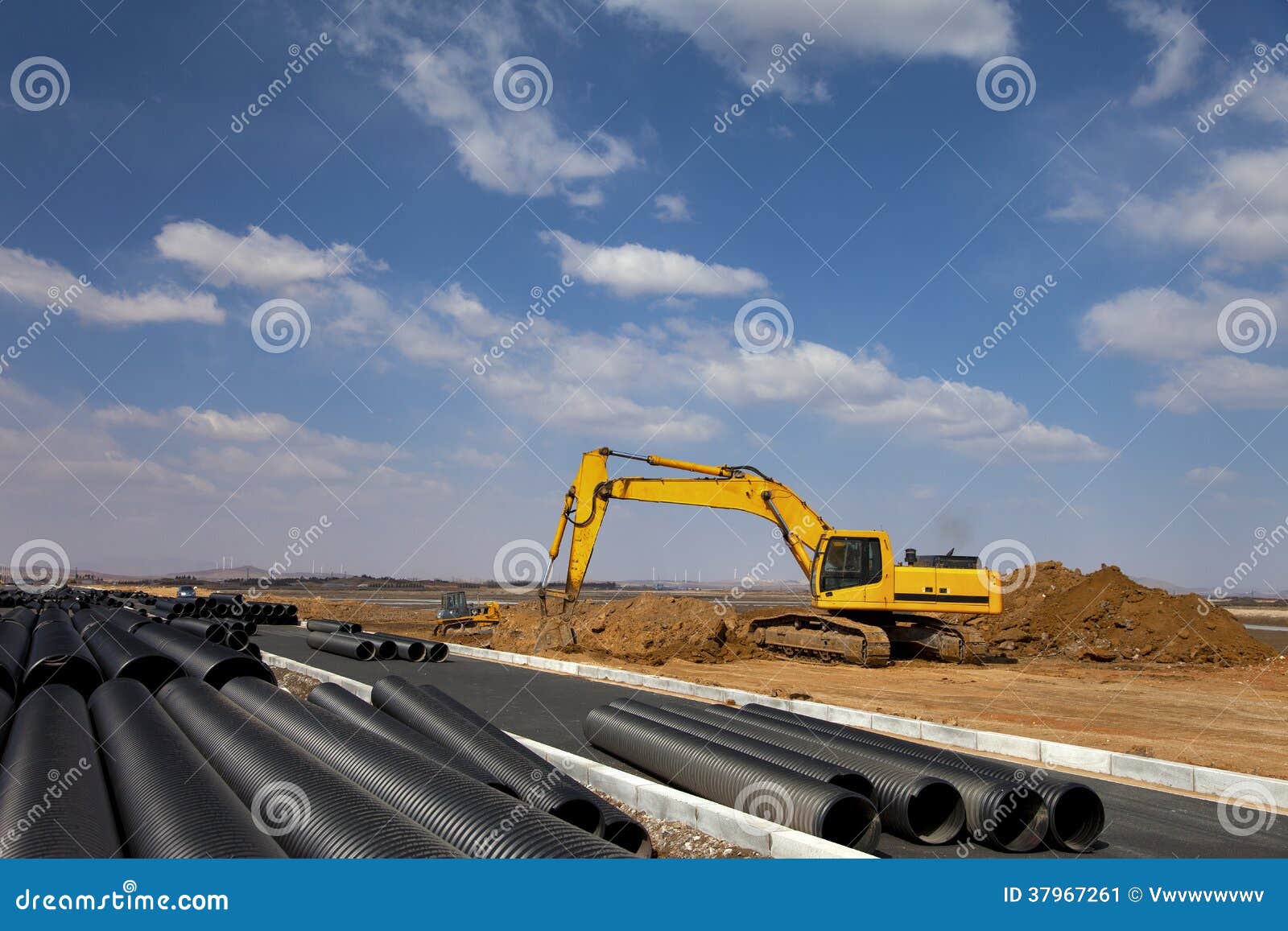 An Excavator is Digging a Ditch Alongside a Newly Built Road Stock ...