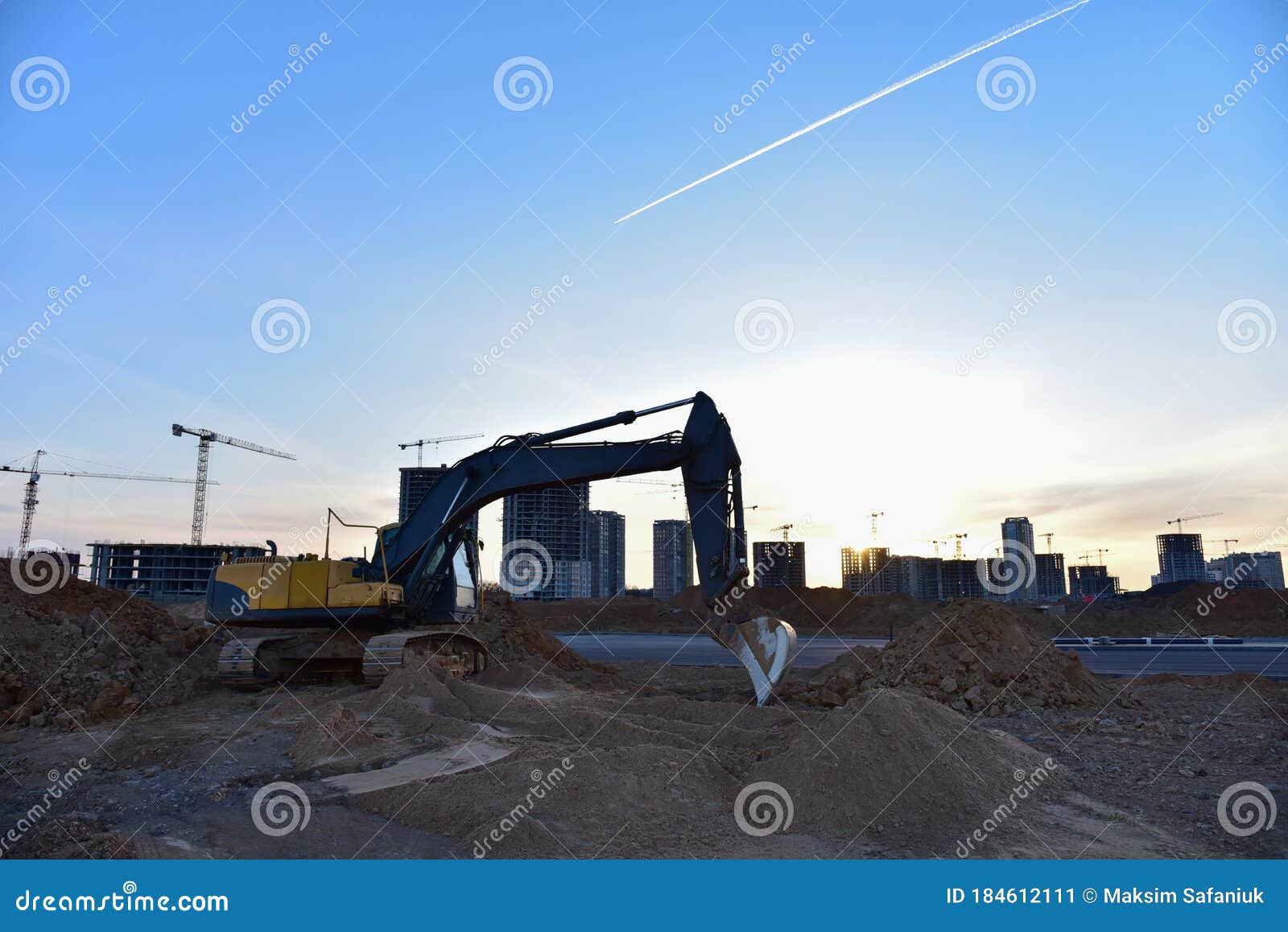 Excavator and Tower Crane at Construction Site on Sunset Background ...