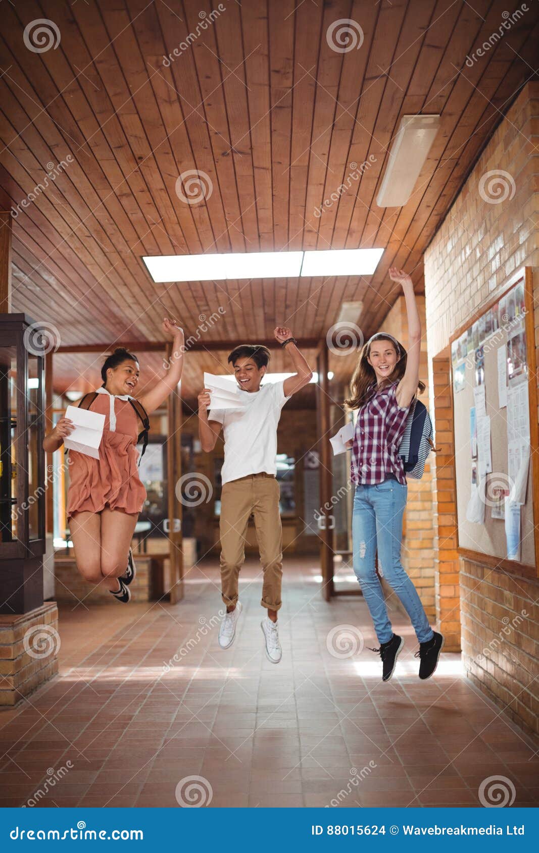 Excited Classmates Jumping with Grade Cards in Corridor Stock Photo ...
