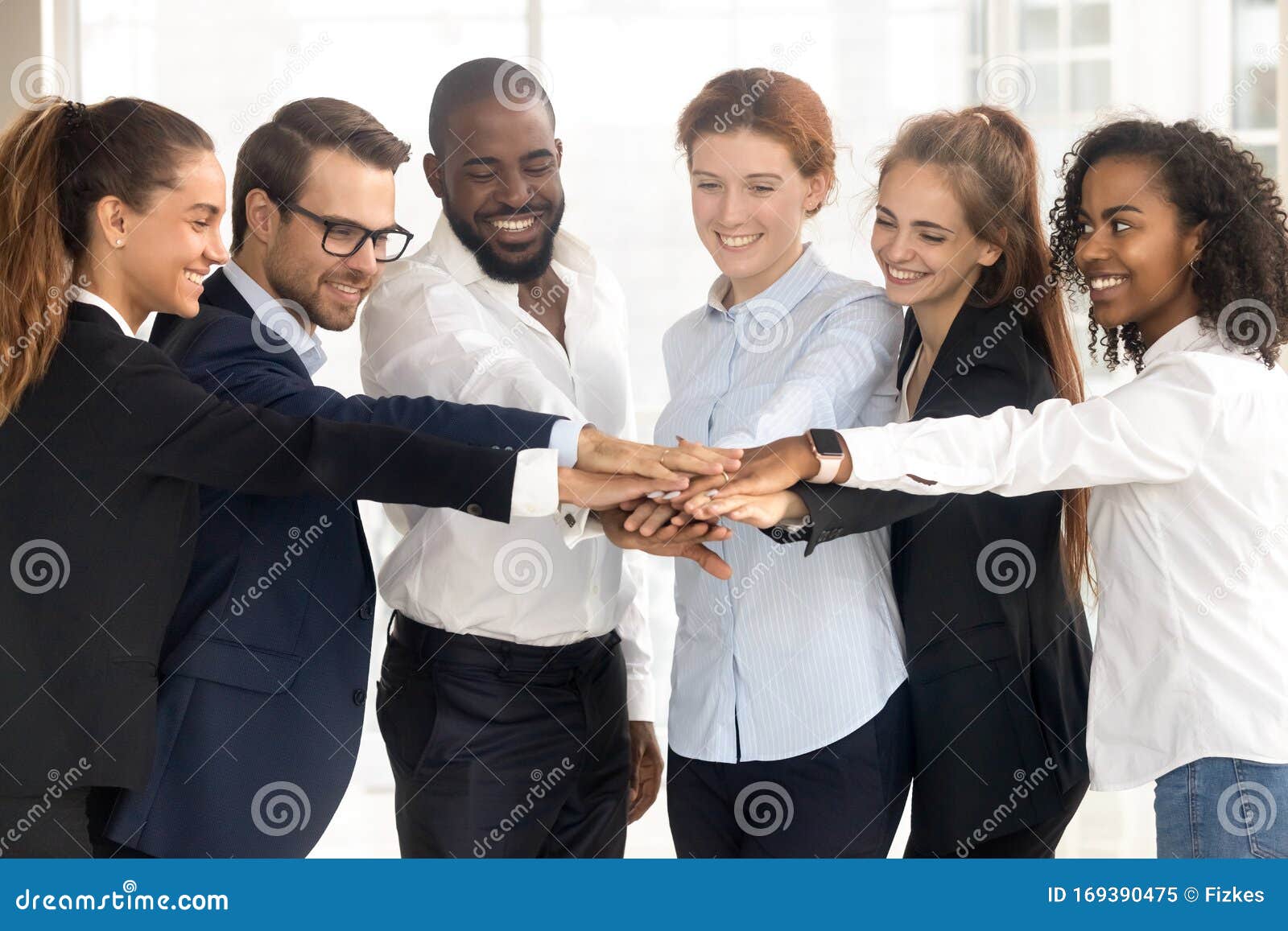 Excited Multiethnic Employees Stack Hands Showing Support and Unity ...