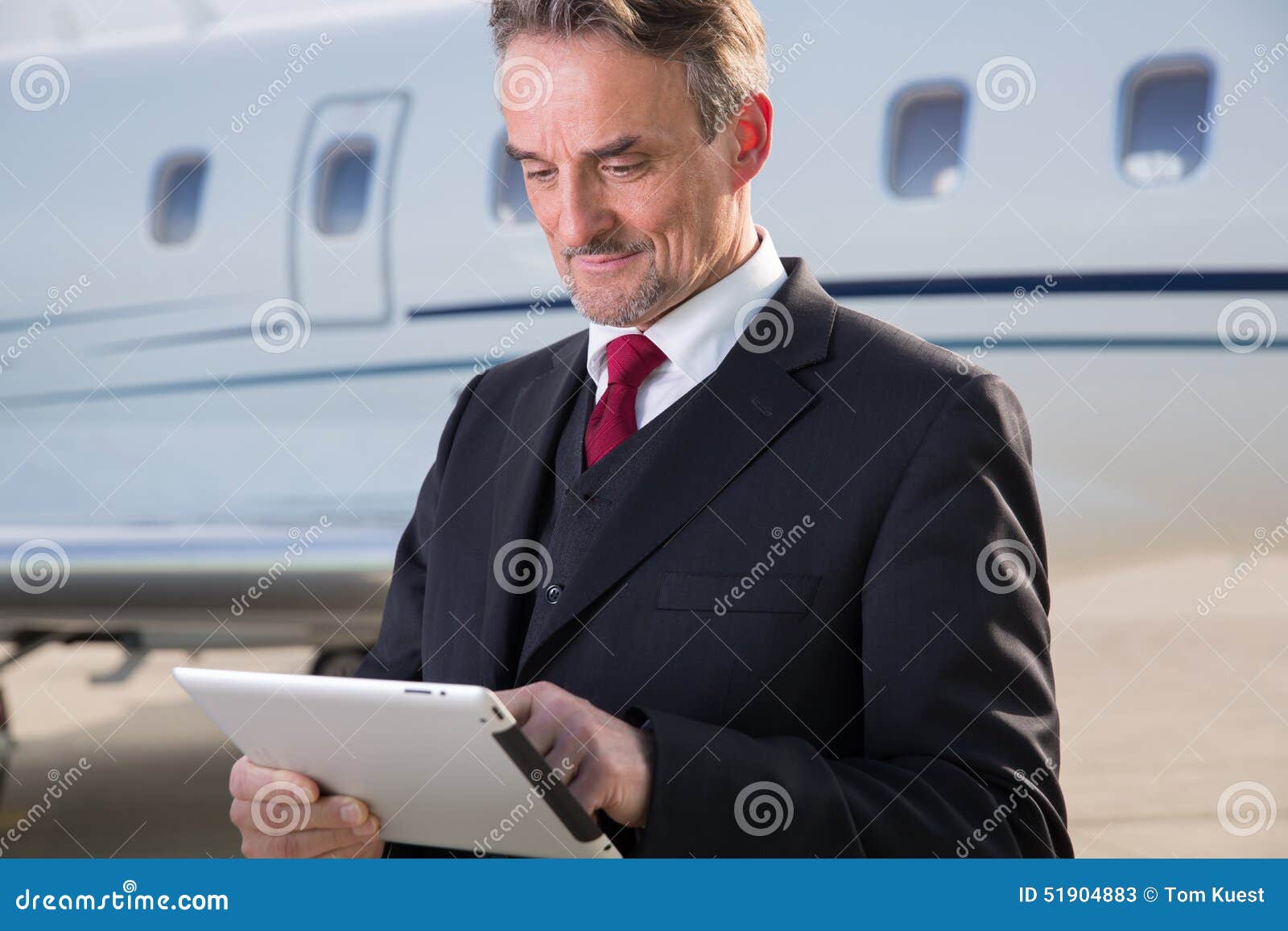 Executive Business Man in Front of Corporate Jet Looking at Tabl Stock ...