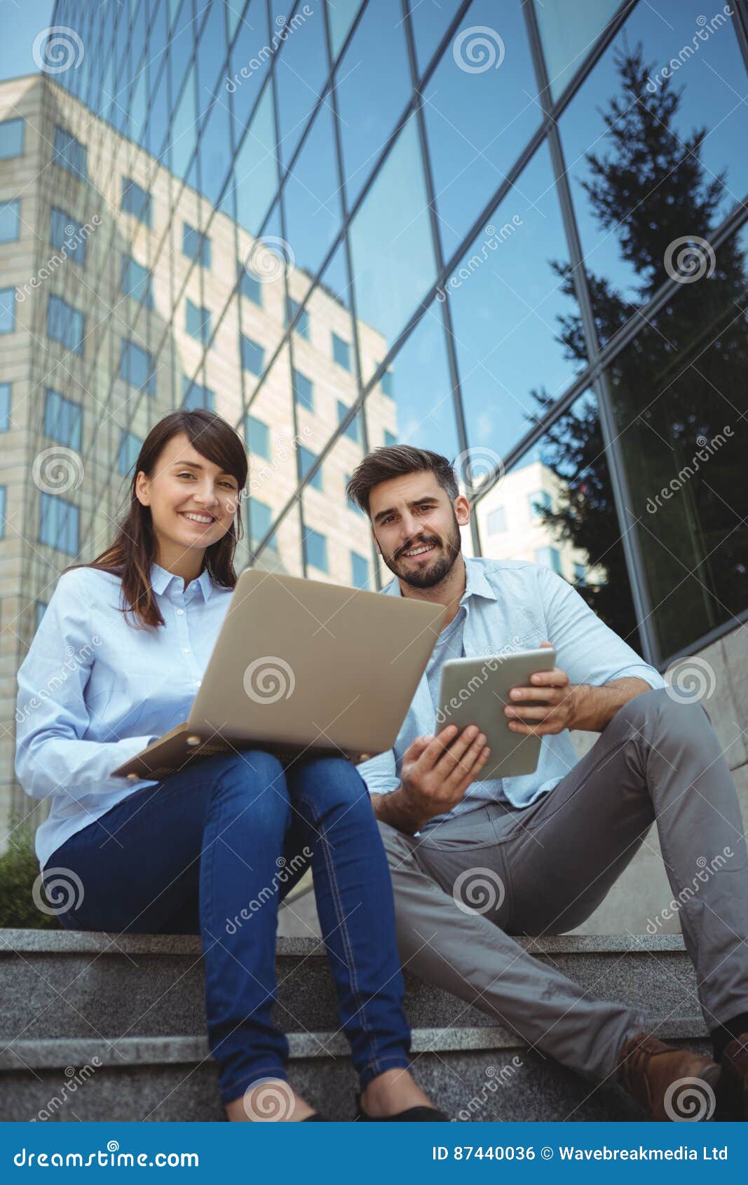 Executives Using Laptop and Digital Tablet Outside Office Building ...