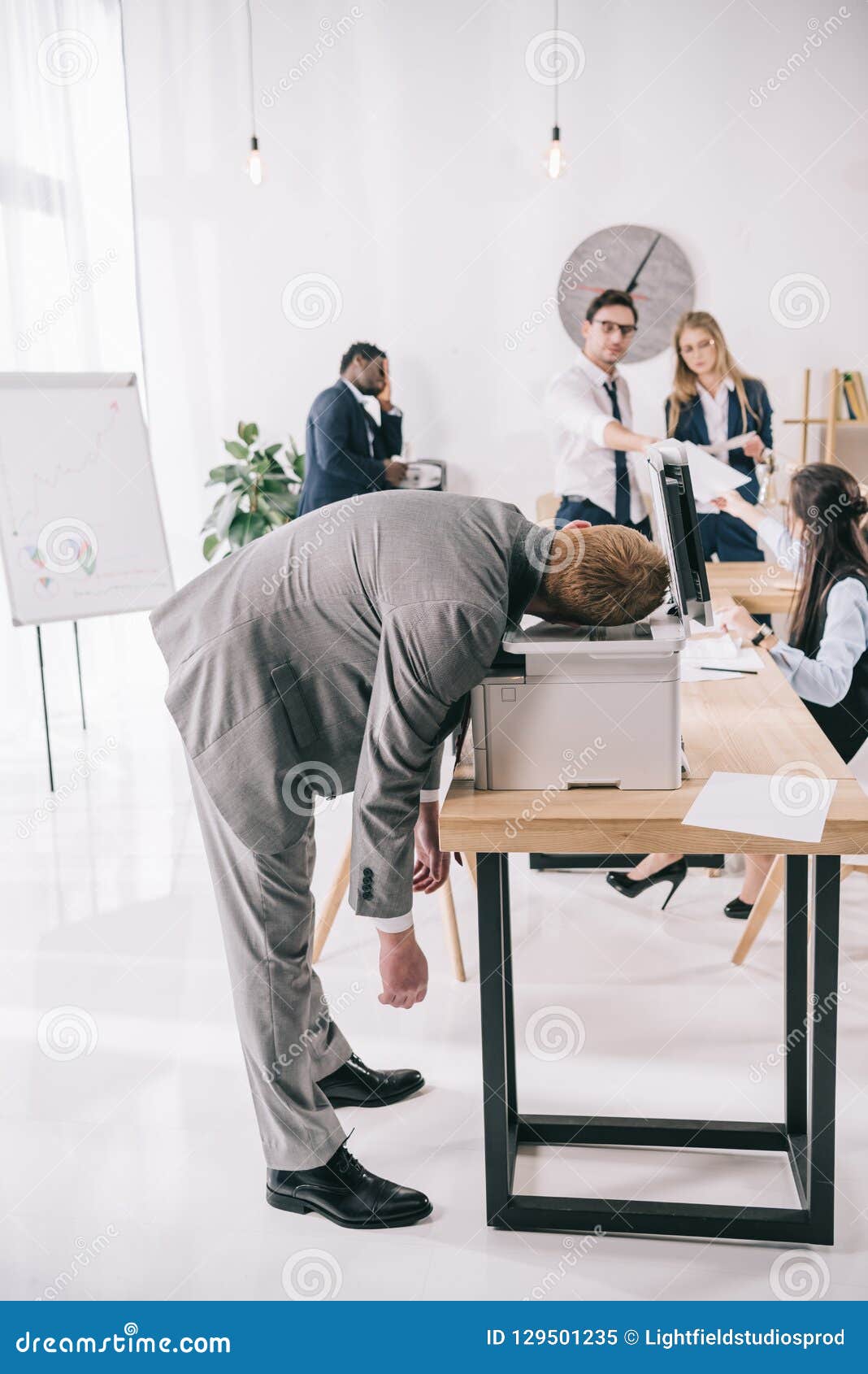 Exhausted Businessman Sleeping on Copier at Office while Colleagues ...