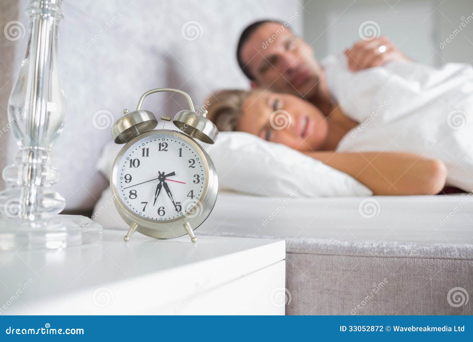Exhausted Couple Looking at Alarm Clock Stock Photo - Image of cushions ...
