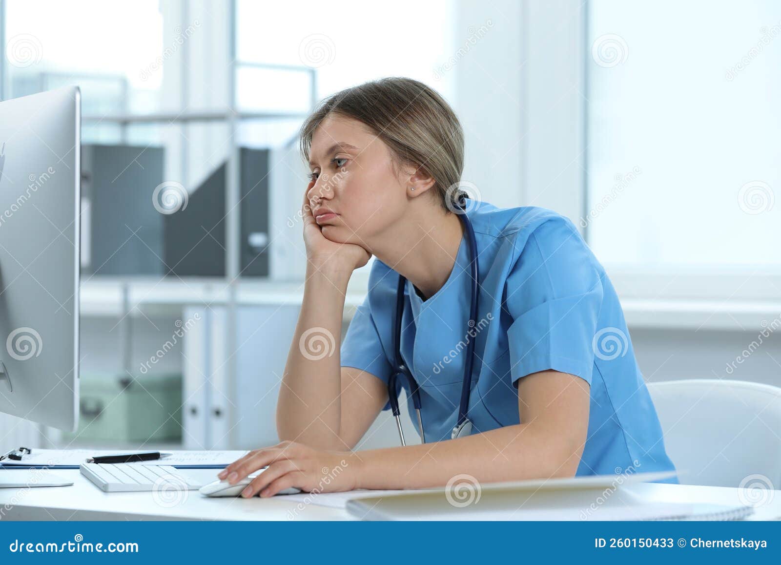 Exhausted Doctor Working with Computer at Table in Hospital Stock Image ...