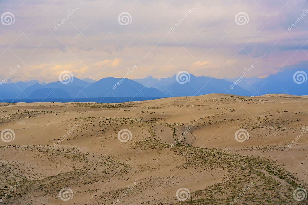 Expansive Desert Dunes Under a Dramatic Sky with Distant Mountains ...