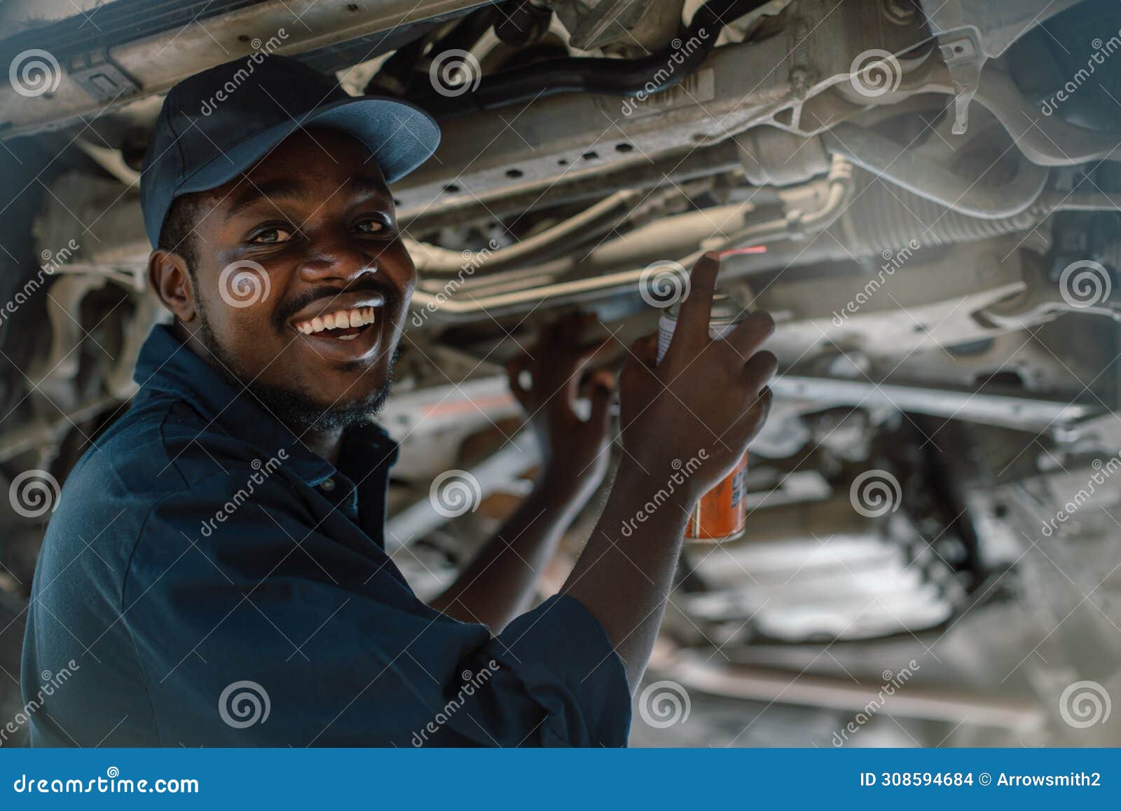 An Expert African Auto Mechanic Sprays Lubricant on a Repaired Engine ...