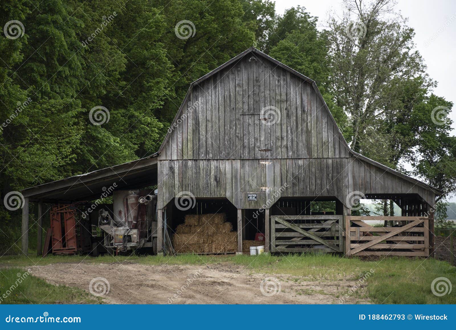 Eye-level Shot of a Wooden Barn Standing Next To Green Trees with a ...