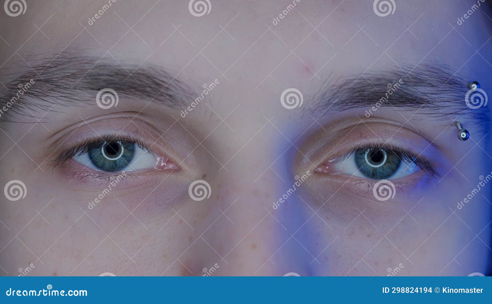 Eyes of Young Guy with Eyebrow Piercing Macro Shot. Blue Light from a ...