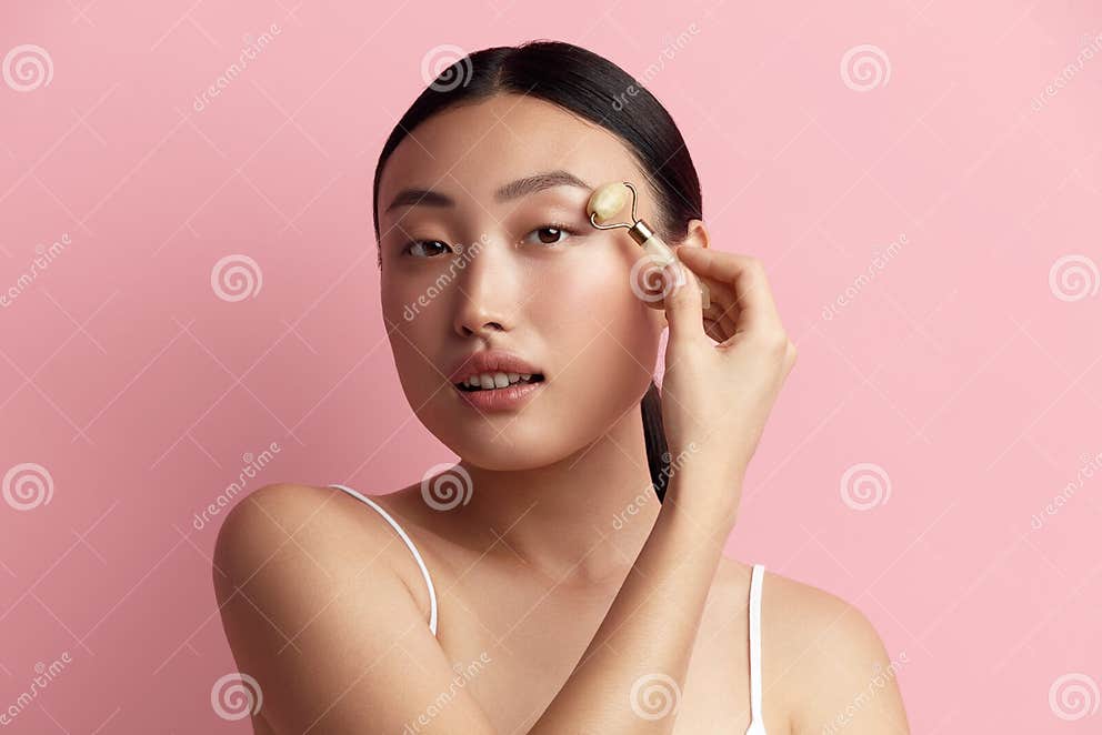 Face Massage Sensual Asian Woman Using Jade Facial Roller For Skin