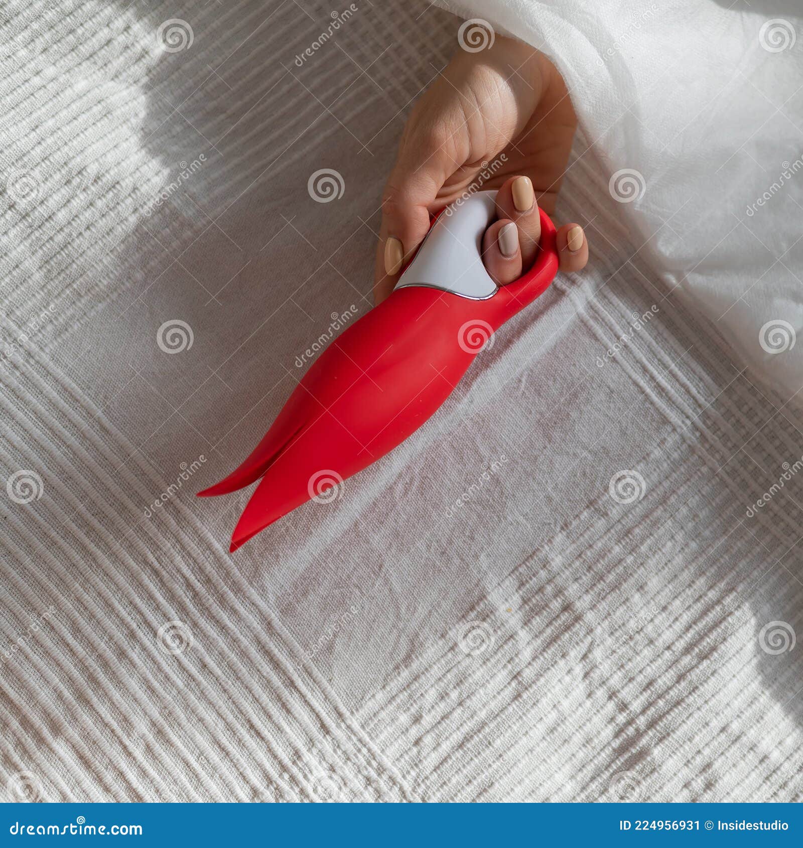 A Faceless Woman Lies In Bed Under A Blanket Holding A Clitoral