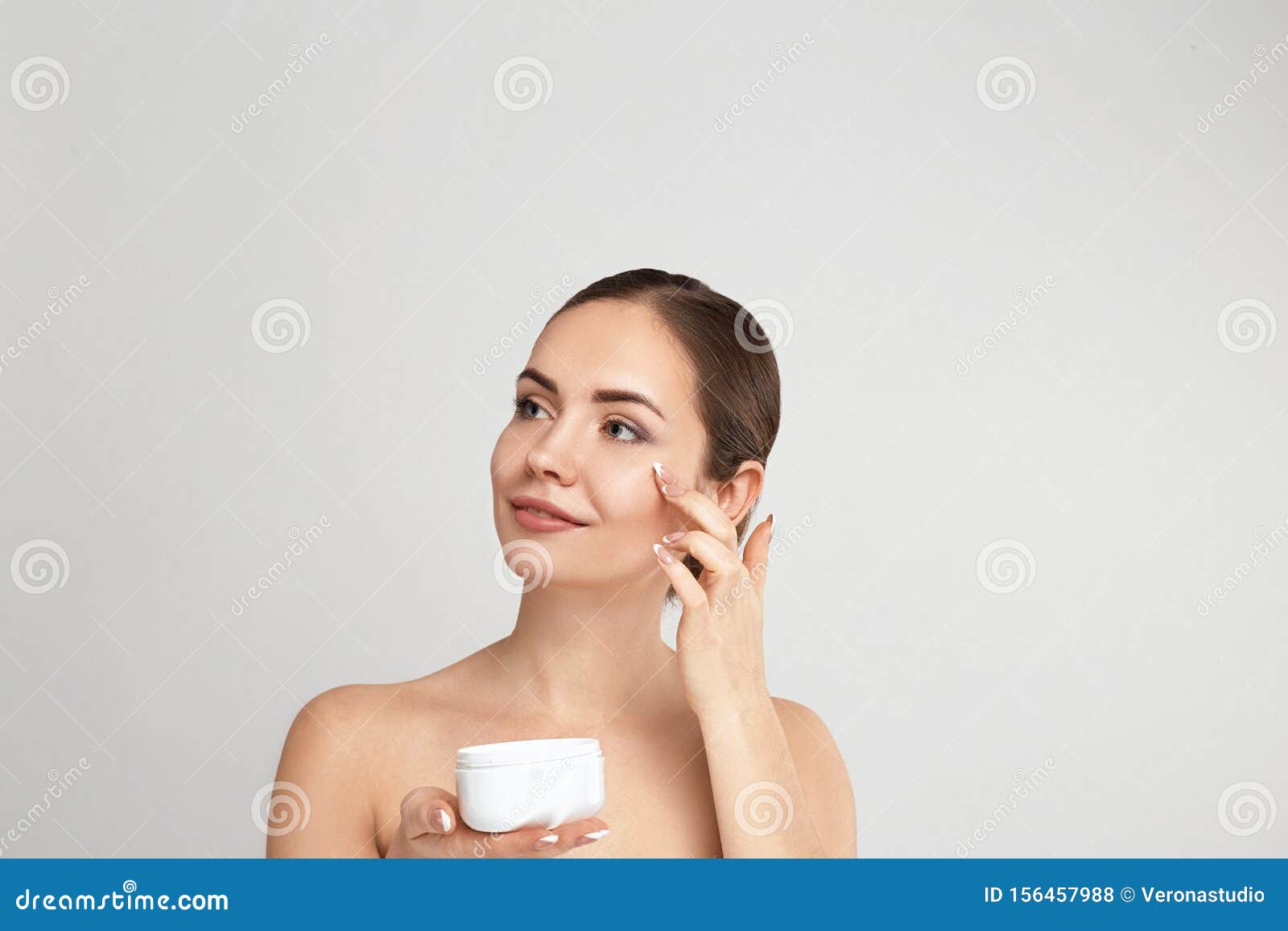 Facial Care Female Applying Cream And Smiling Portrait Of Young Woman