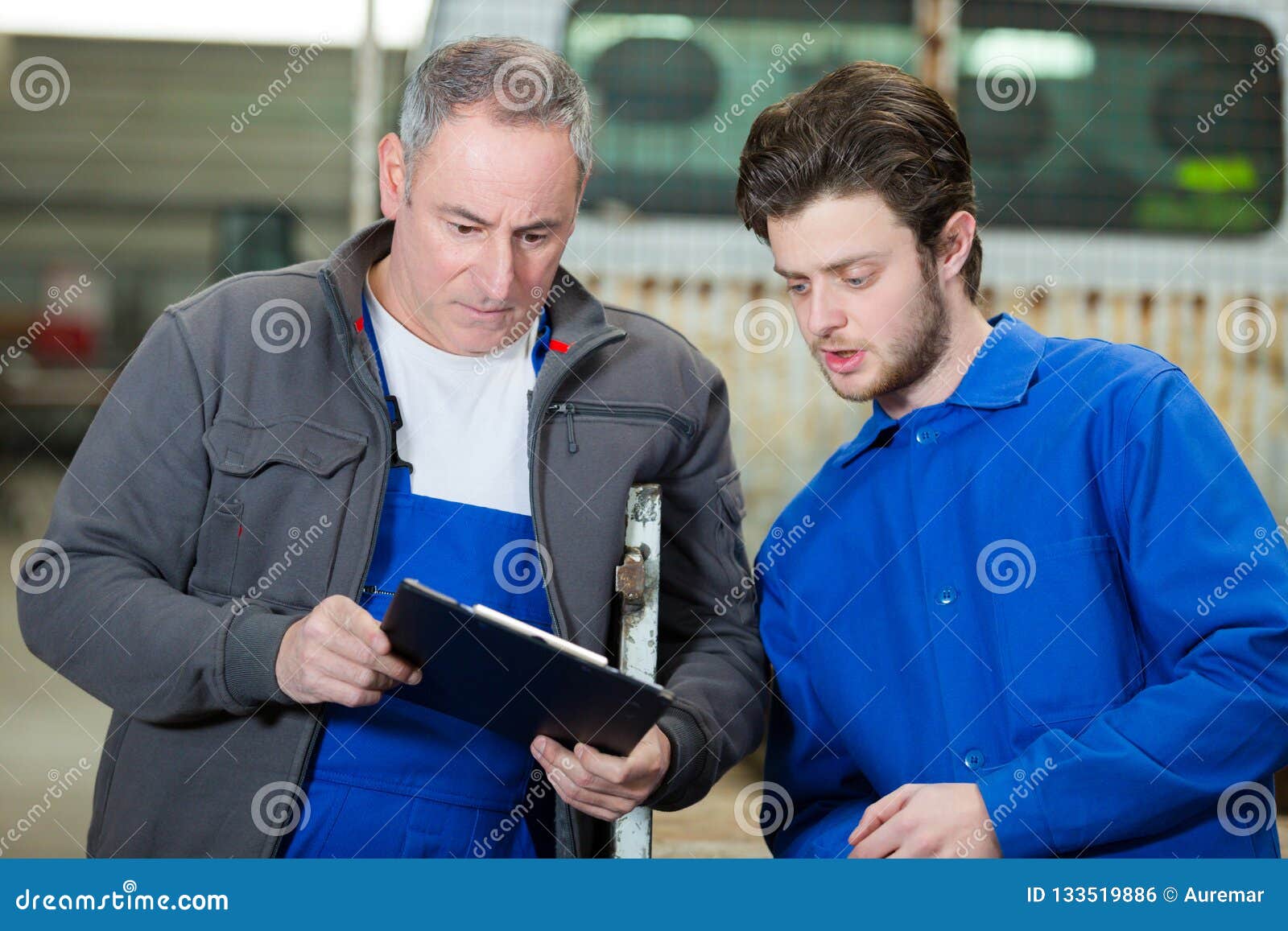 Factory Manager and Apprentice Engineer Looking at Clipboard Stock ...