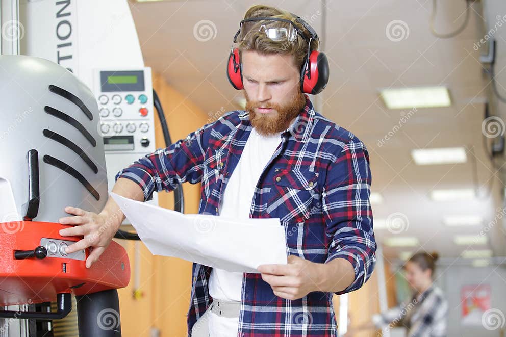 Factory Operative with Paperwork Setting Up Machinery Stock Image ...