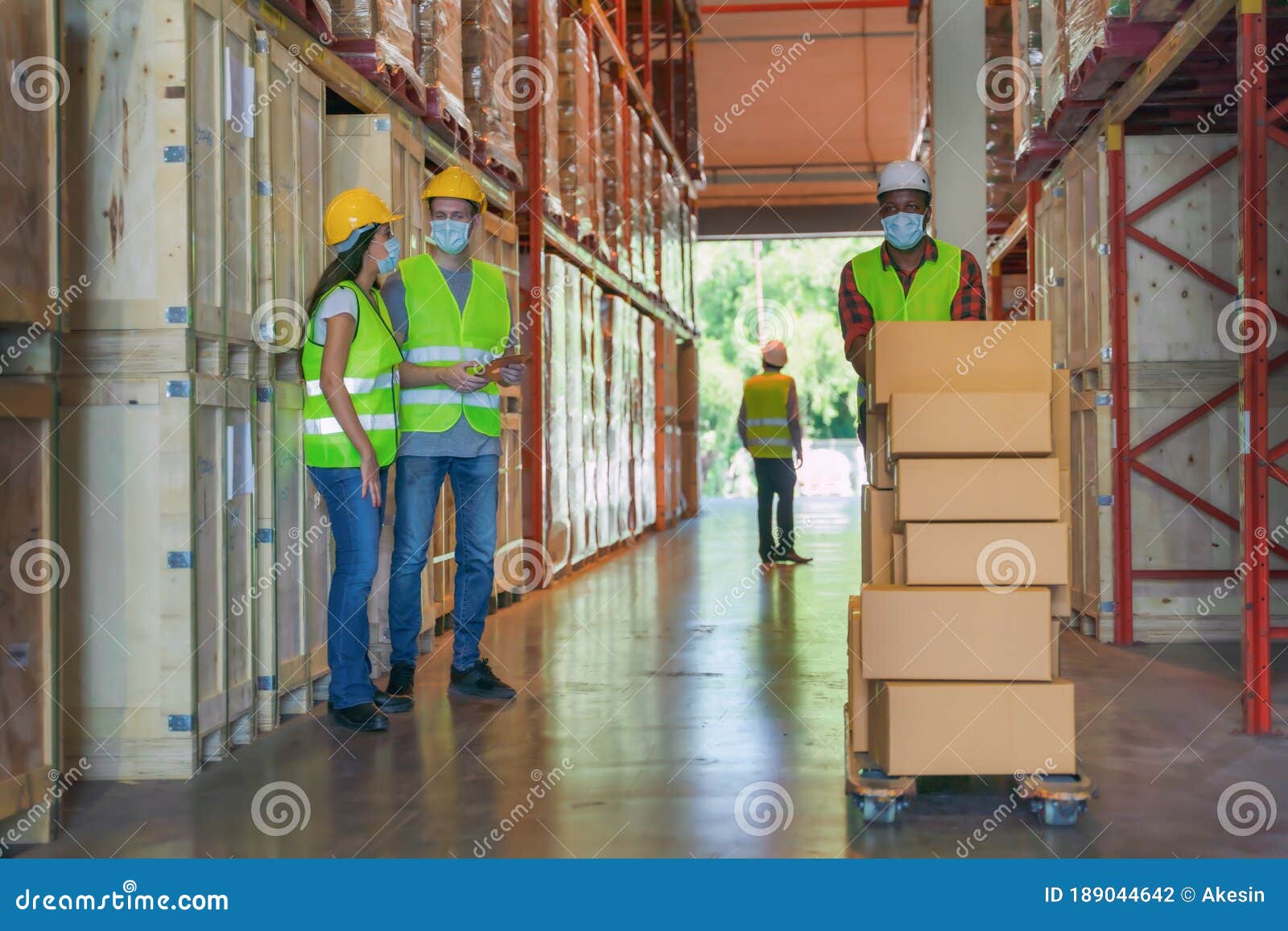 Warehouse Workers In Safety Uniform Working In Warehouse Full Of Tall ... Warehouse Workers In Safety Uniform Working In Warehouse Full Of Tall ...