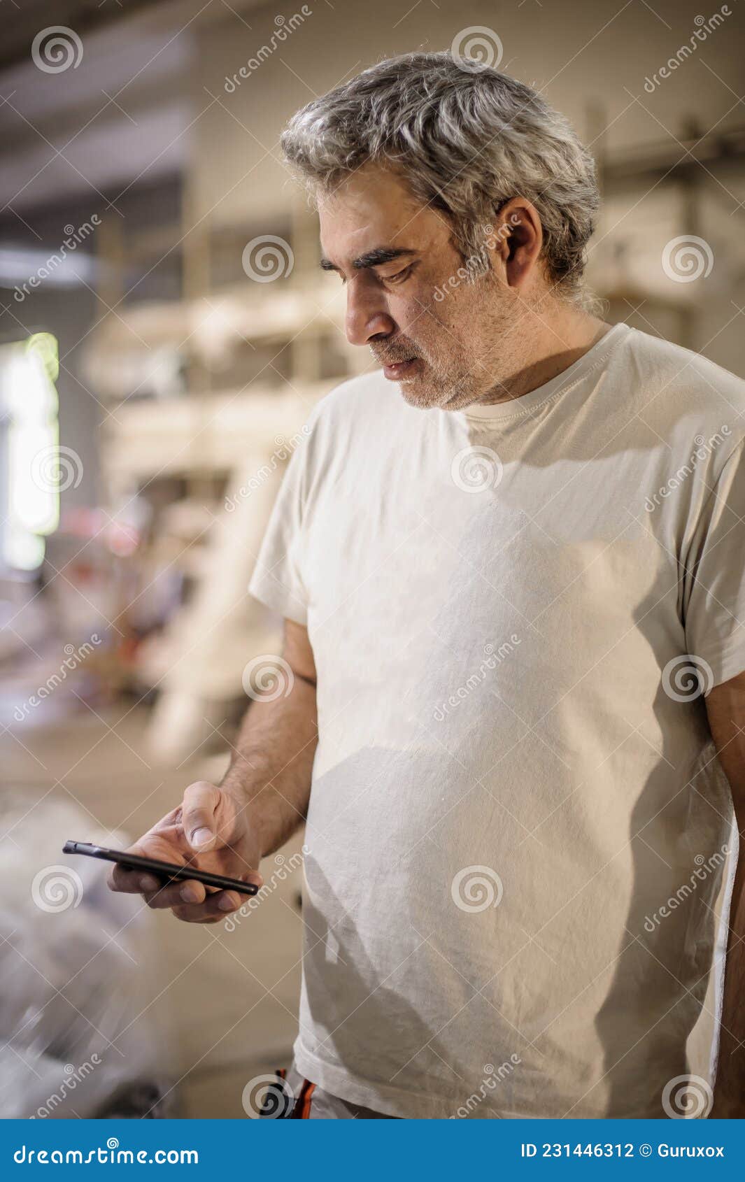 Factory Worker Resting and Using Mobile Phone in Workshop Stock Photo ...