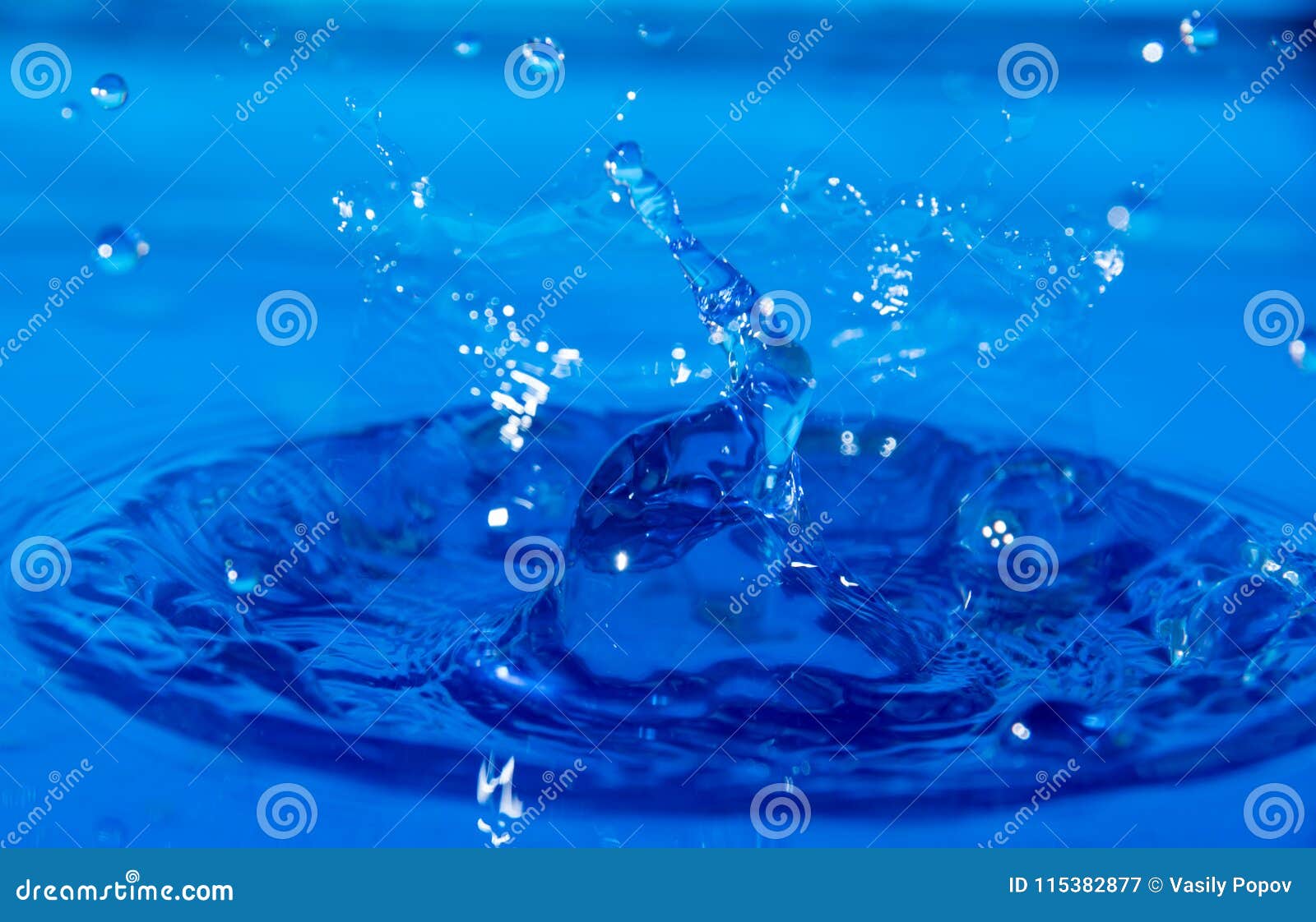 A Falling Drop in the Blue Water. the Waves Diverge from the Drop Stock ...