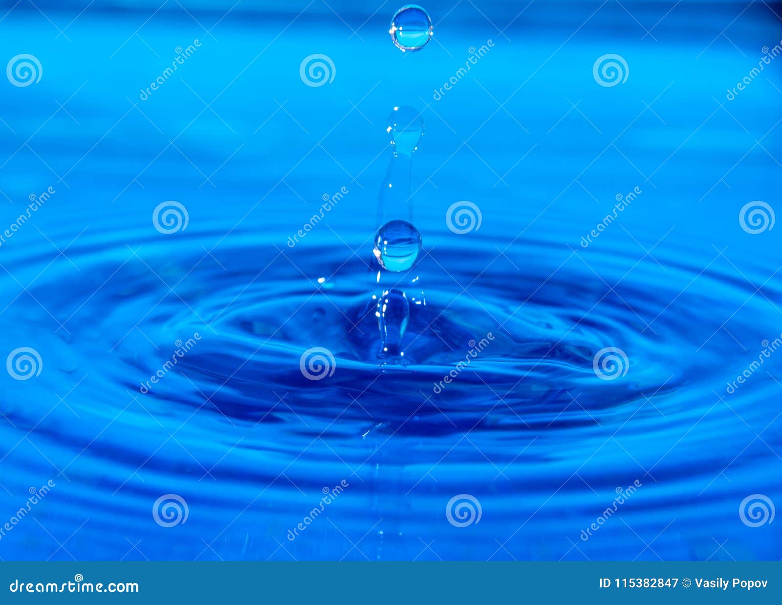A Falling Drop in the Blue Water. the Waves Diverge from the Drop Stock ...