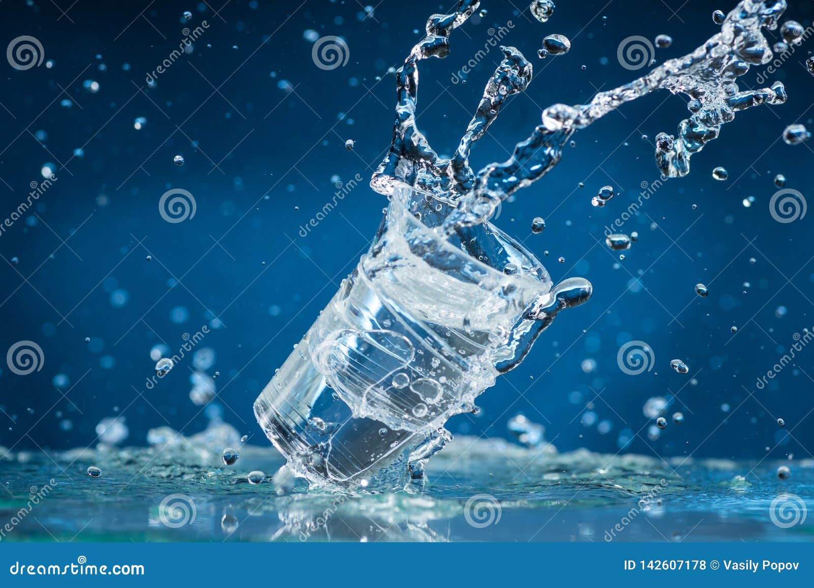 Falling Small Glasses and Spilling Water on a Blue Background Stock ...