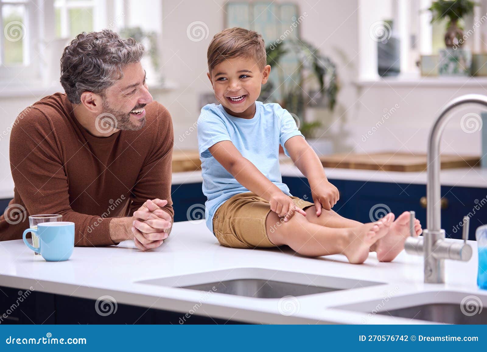 Family with Father in Kitchen with Son Sitting on Counter Stock Photo ...
