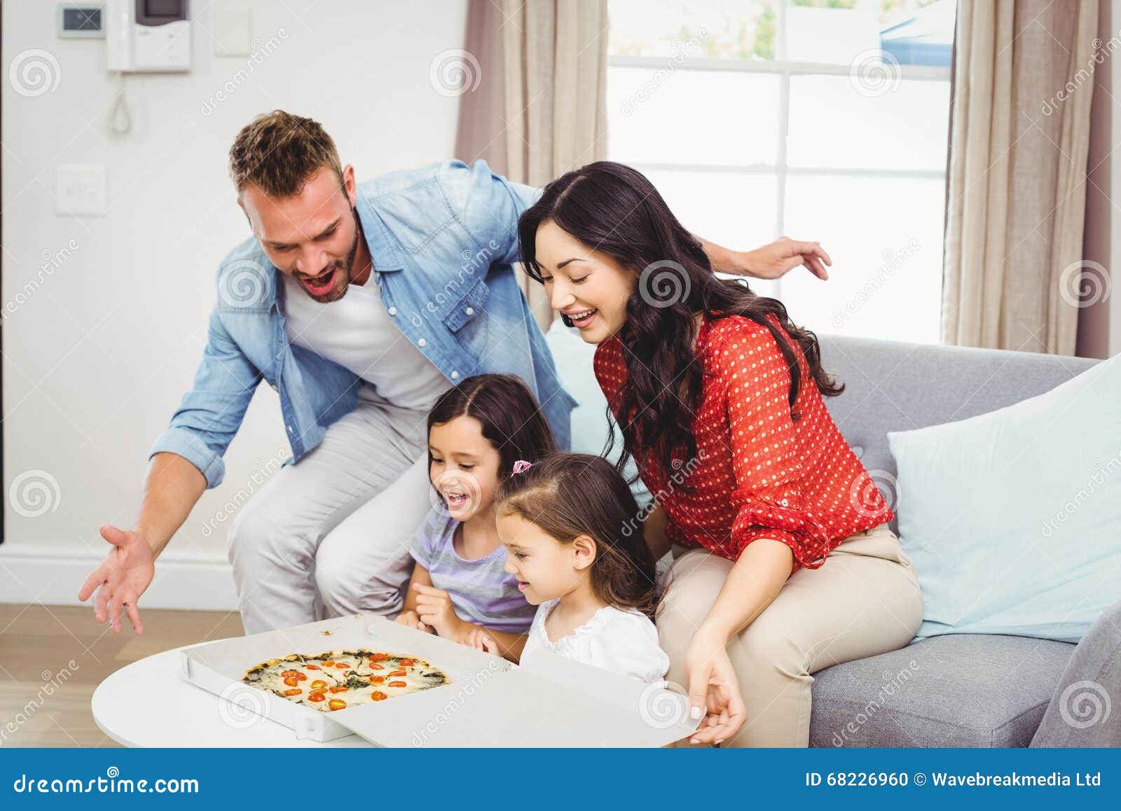 Family of Four Looking at Pizza on Table Stock Photo - Image of ...
