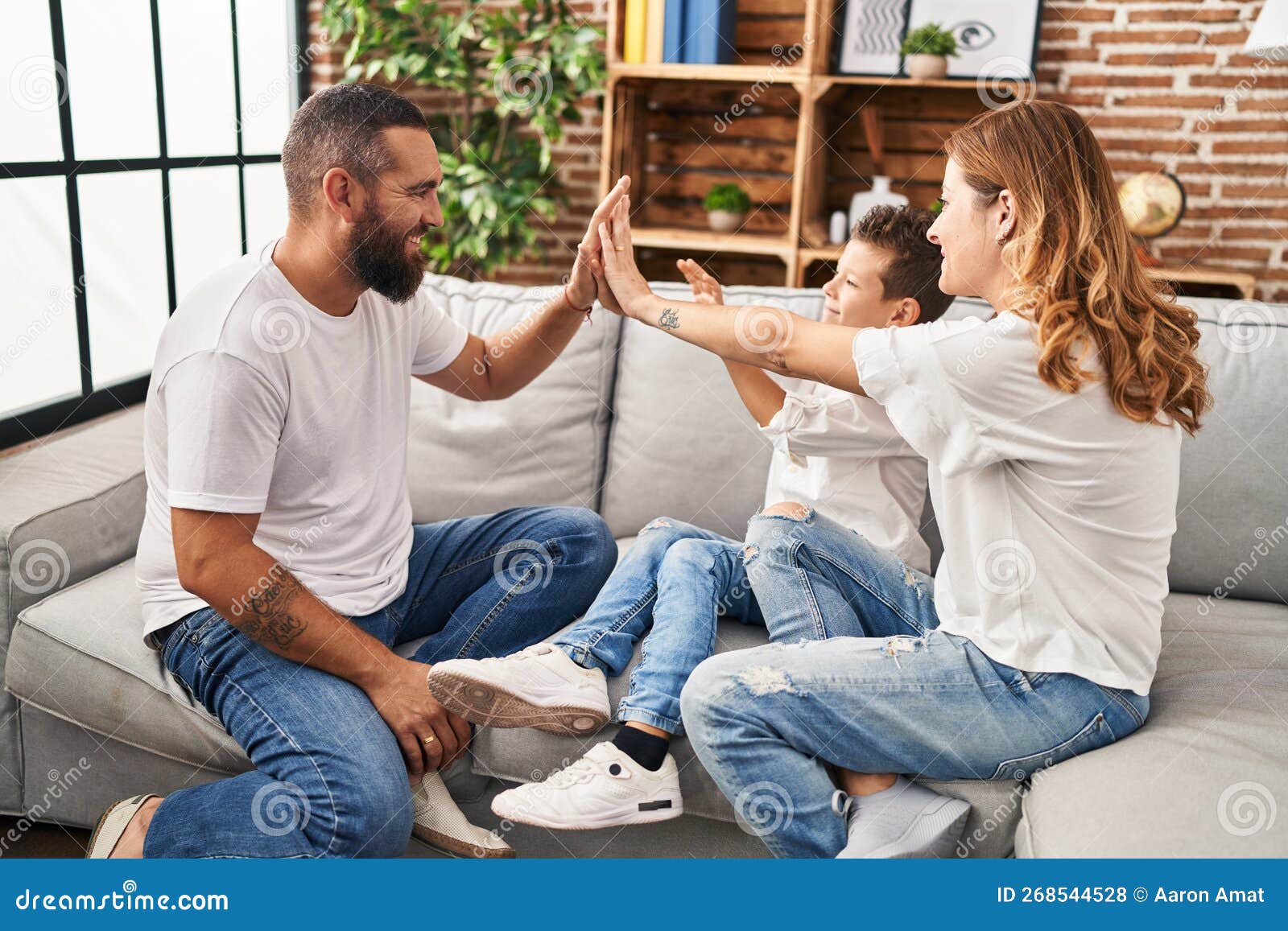 Family High Five with Hands Raised Up Sitting on Sofa at Home Stock ...