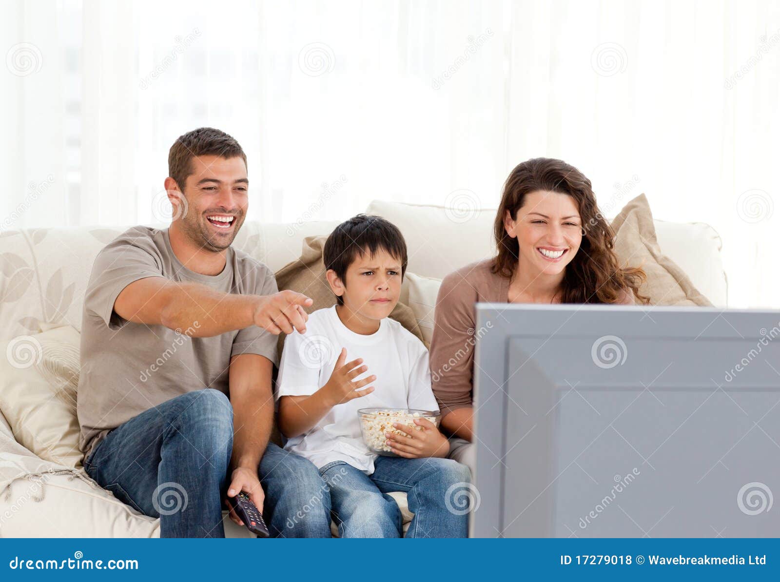 Family Laughing while Watching Television Together Stock Photo - Image ...