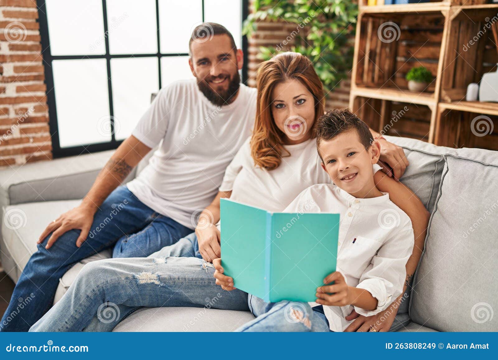 Family Reading Book Sitting on Sofa at Home Stock Image - Image of read ...