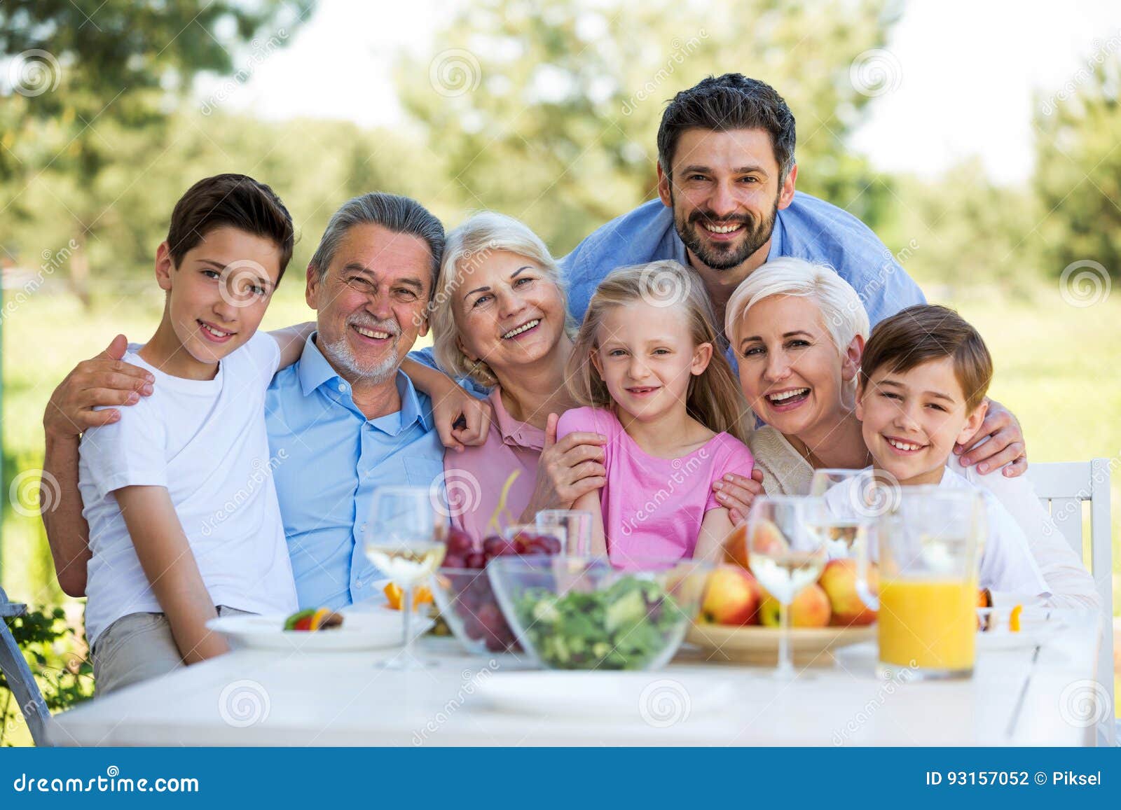 Family Sitting at Table Outdoors, Smiling Stock Photo - Image of family ...