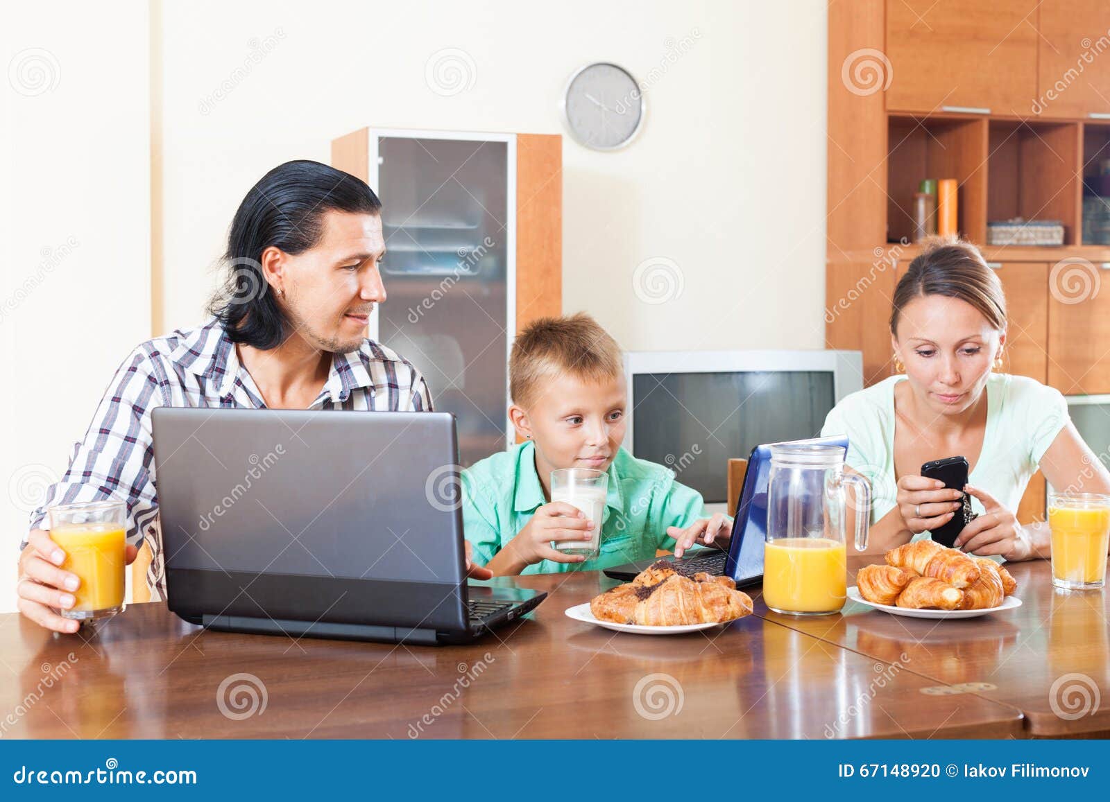 Family of Three Using Electronic Devices during Breakfast Stock Photo ...