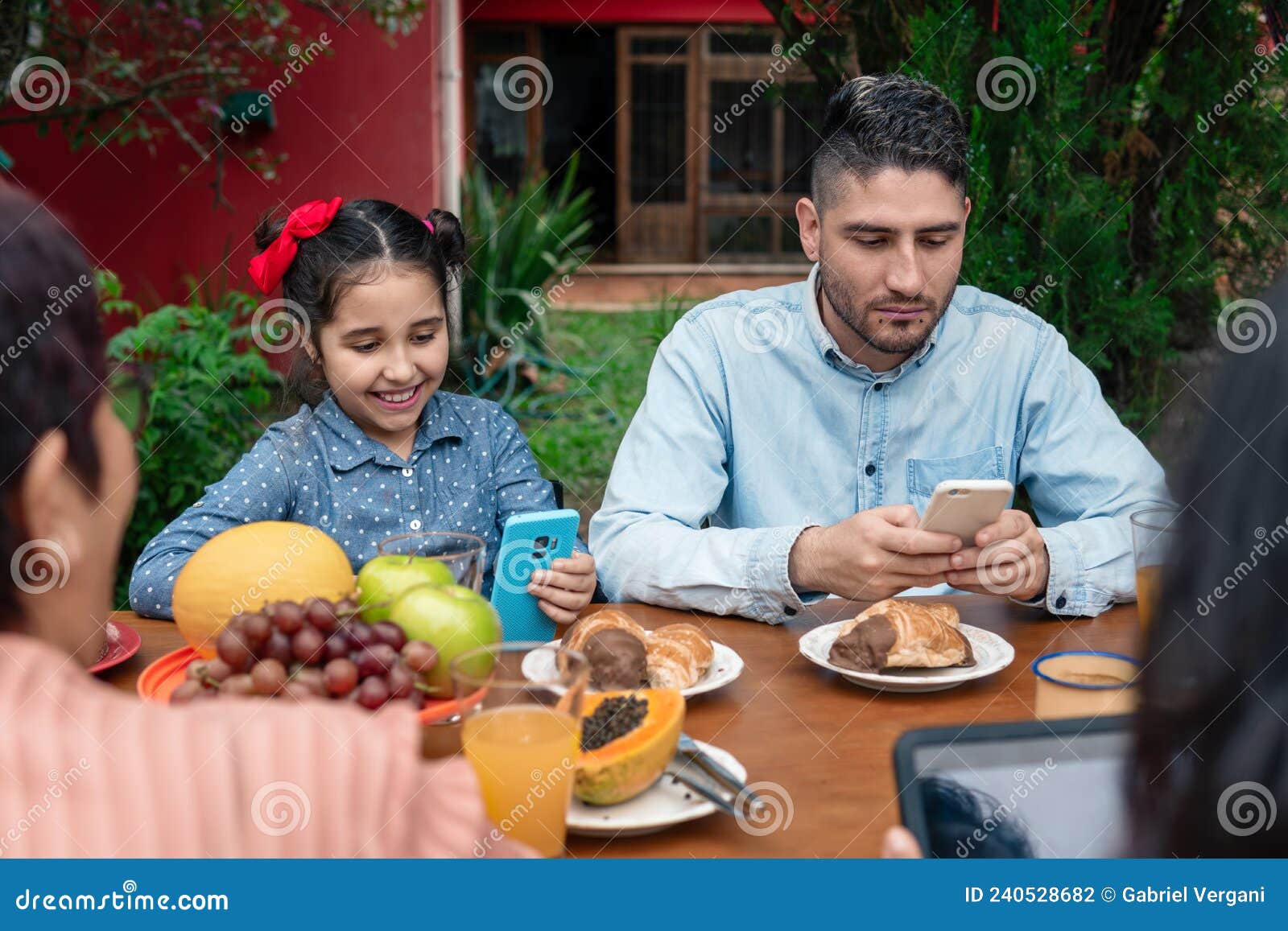 Family Using Mobile and Having Breakfast in Table Outside Stock Photo ...