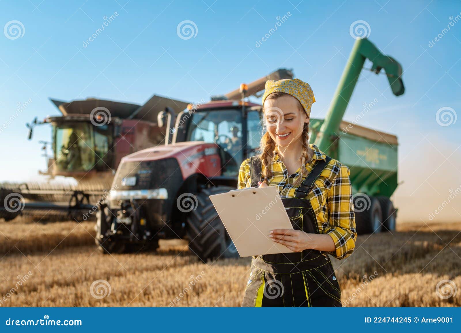 Farmer on Grain Field with Tractor and Combine Harvester in Background ...