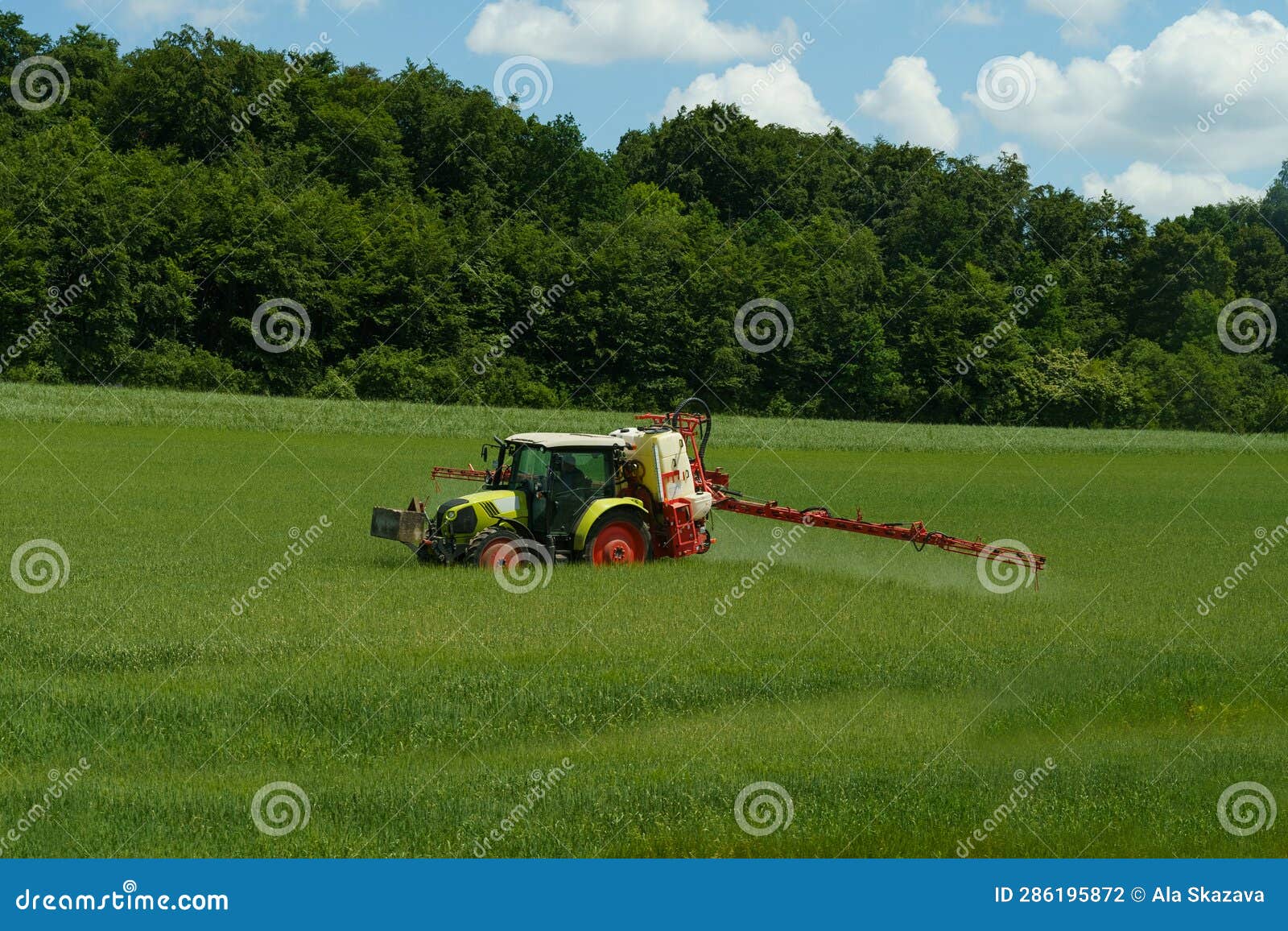 A Farmer Sprays Fertilizer through a Sprayer while Riding in a Tractor ...