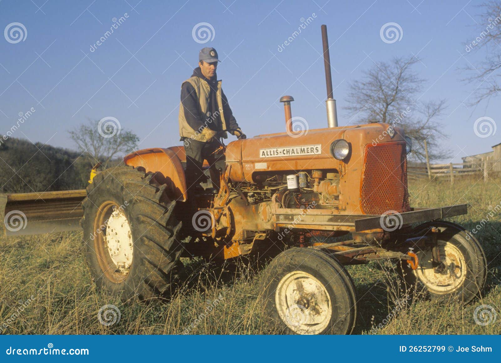 Farmer standing on tractor editorial stock image. Image of male - 26252799