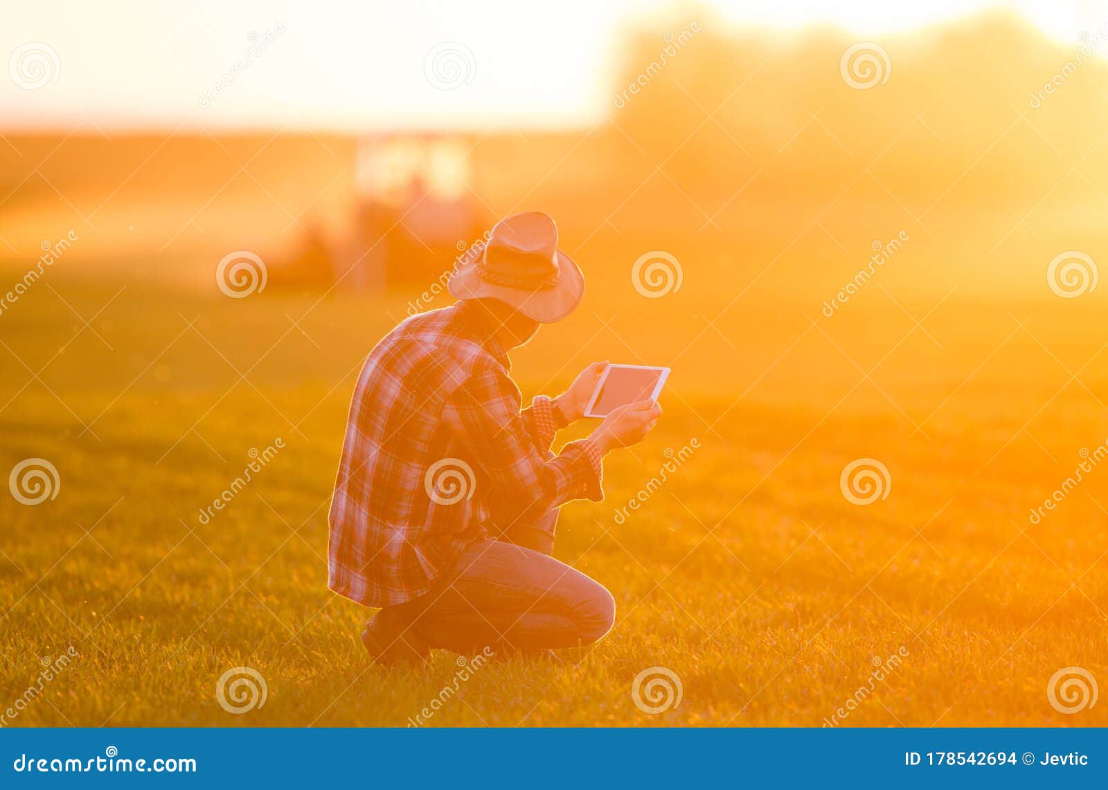 Farmer with Tablet Squatting in Front of Tractor Stock Photo - Image of ...