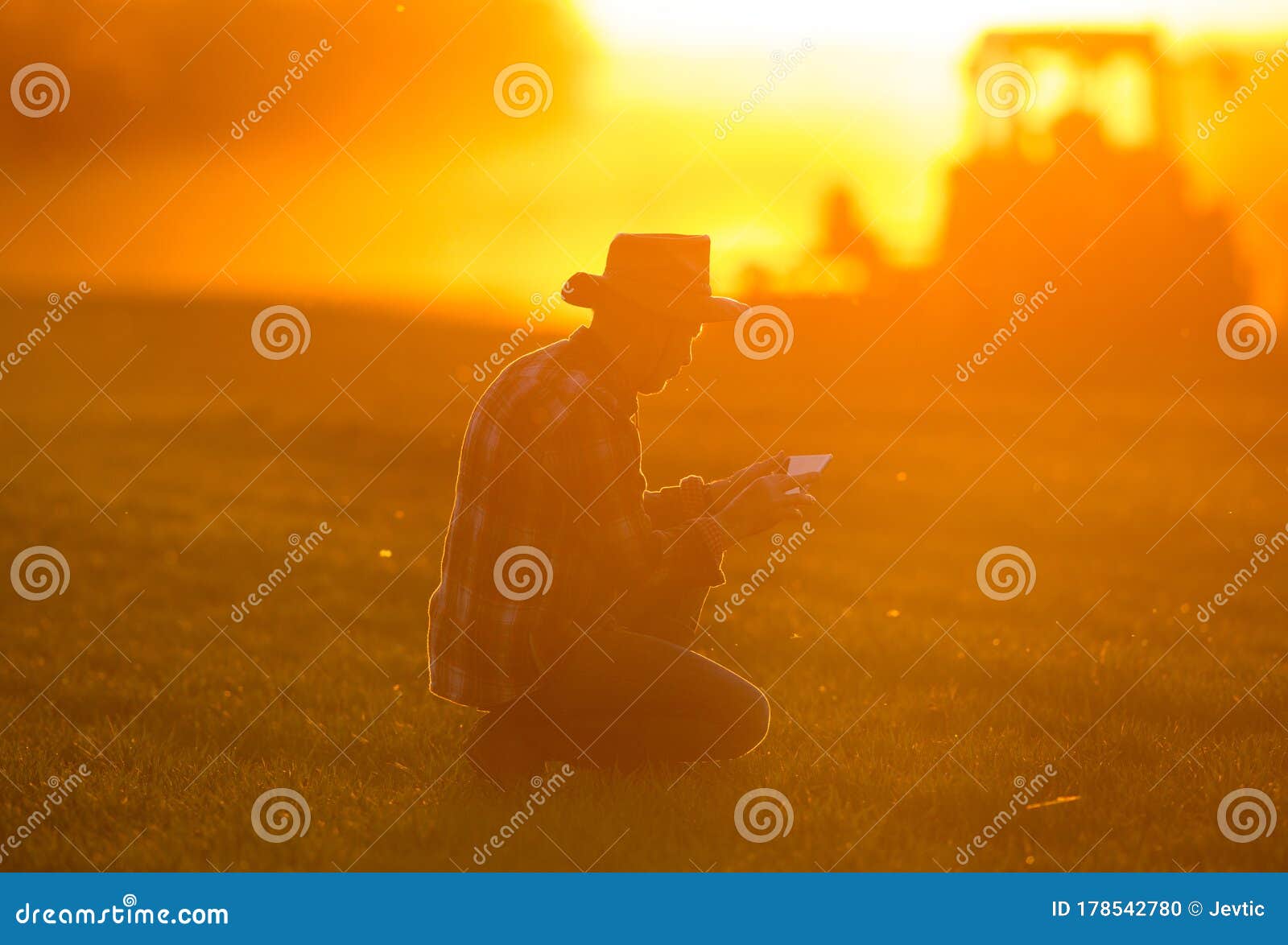 Farmer with Tablet Squatting in Front of Tractor Stock Photo - Image of ...
