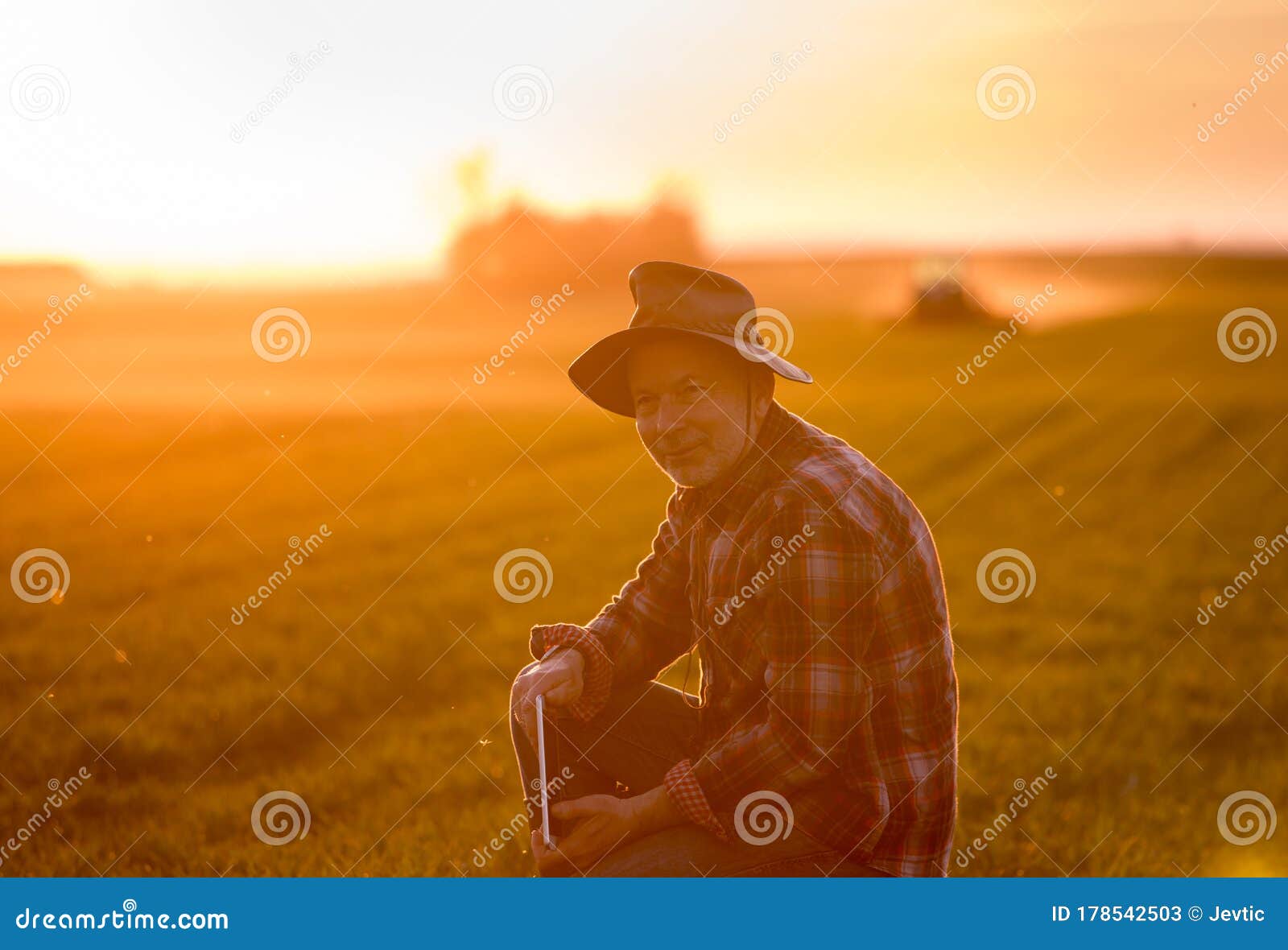 Farmer with Tablet Squatting in Front of Tractor Stock Image - Image of ...