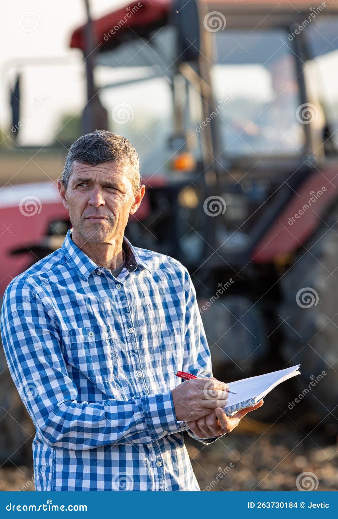 Farmer Writing Notes in Front of Tractor in Field Stock Photo - Image ...