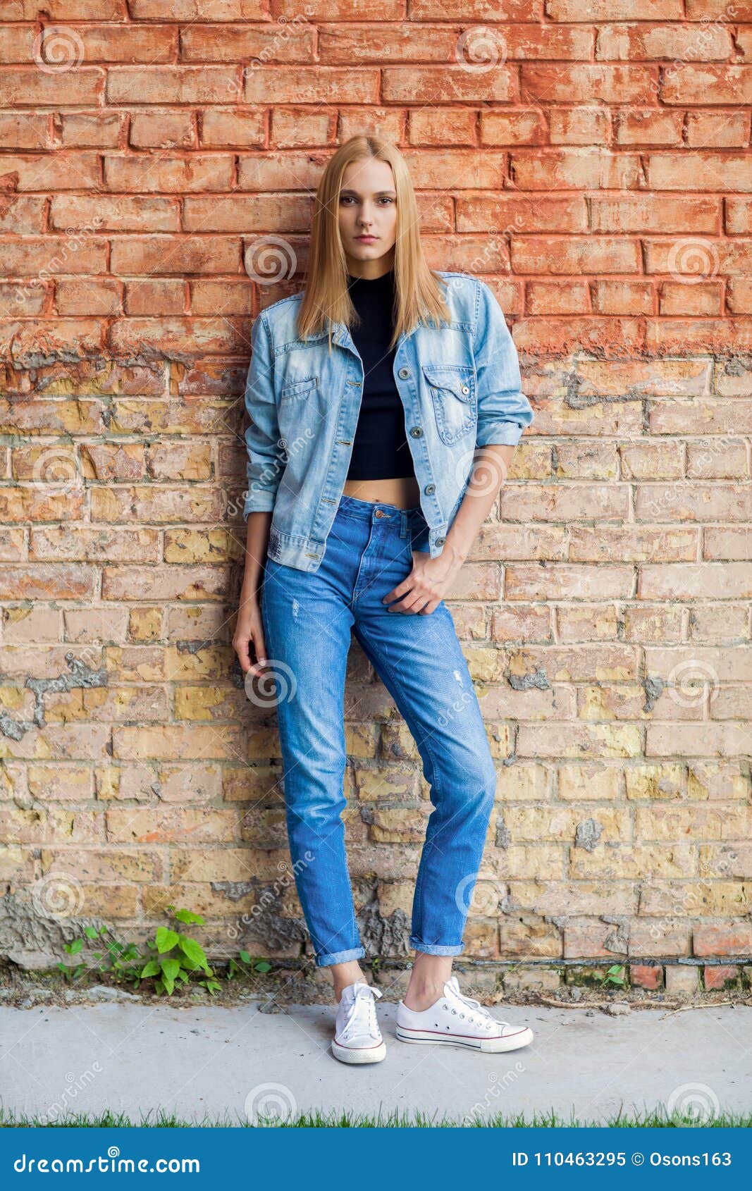 Fashion Girl Standing Near Brick Wall In Denim And Sneakers Vogue