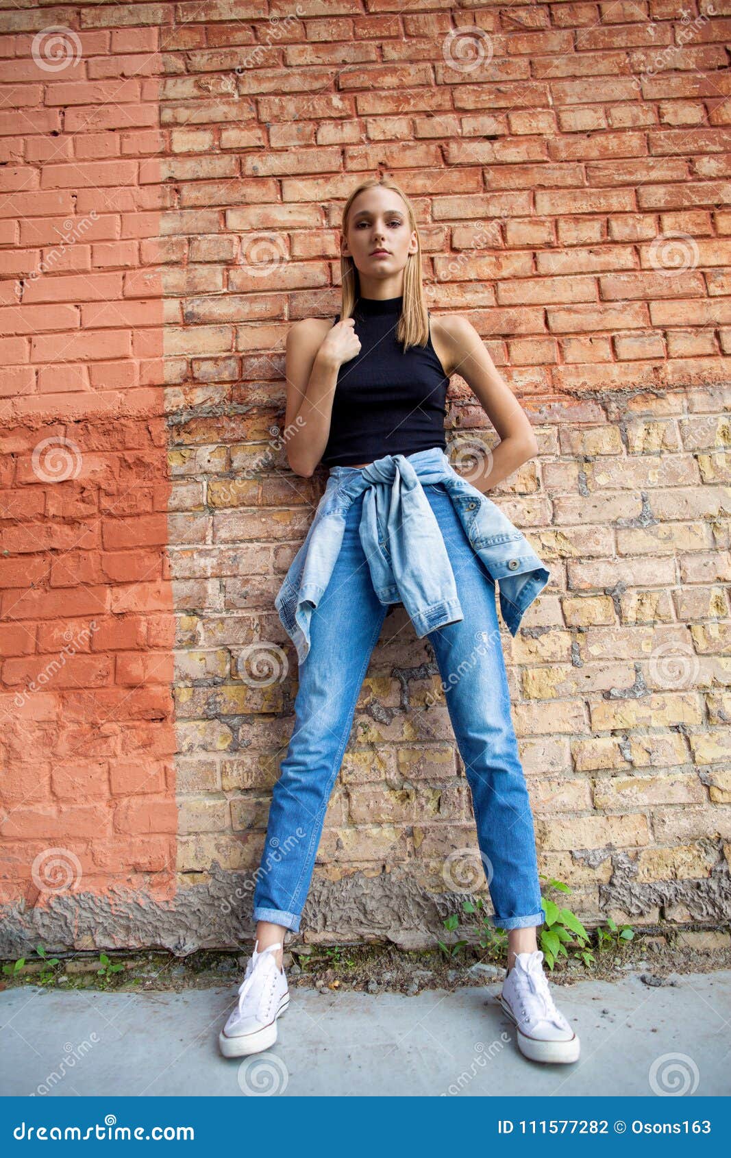 Fashion Girl Standing Near Brick Wall In Denim And Sneakers Vogue