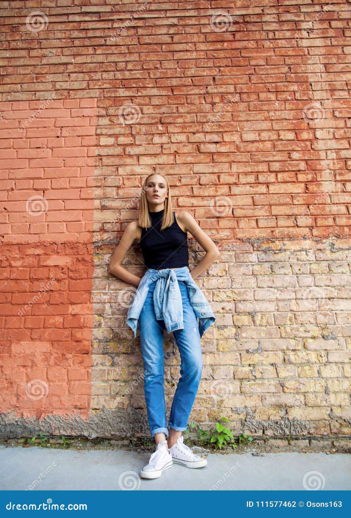 Fashion Girl Standing Near Brick Wall In Denim And Sneakers Vogue