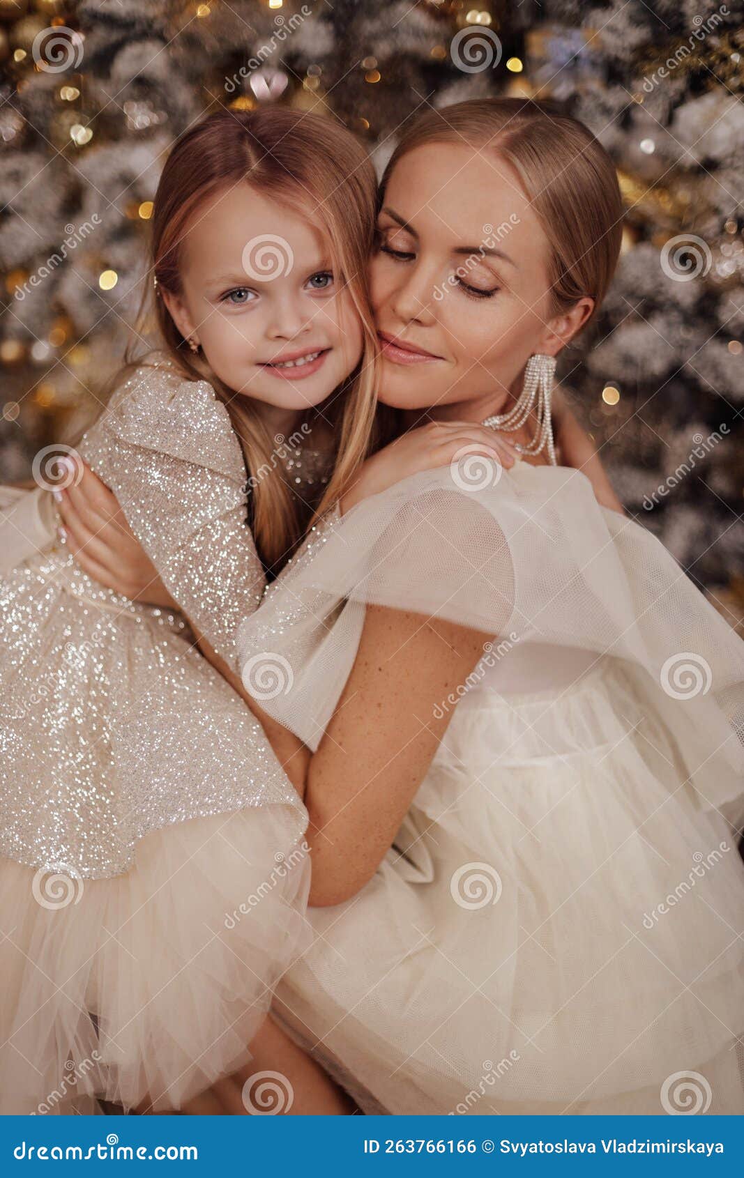 Mother And Her Daughter With Blond Hair In Elegant Dresses Posing In