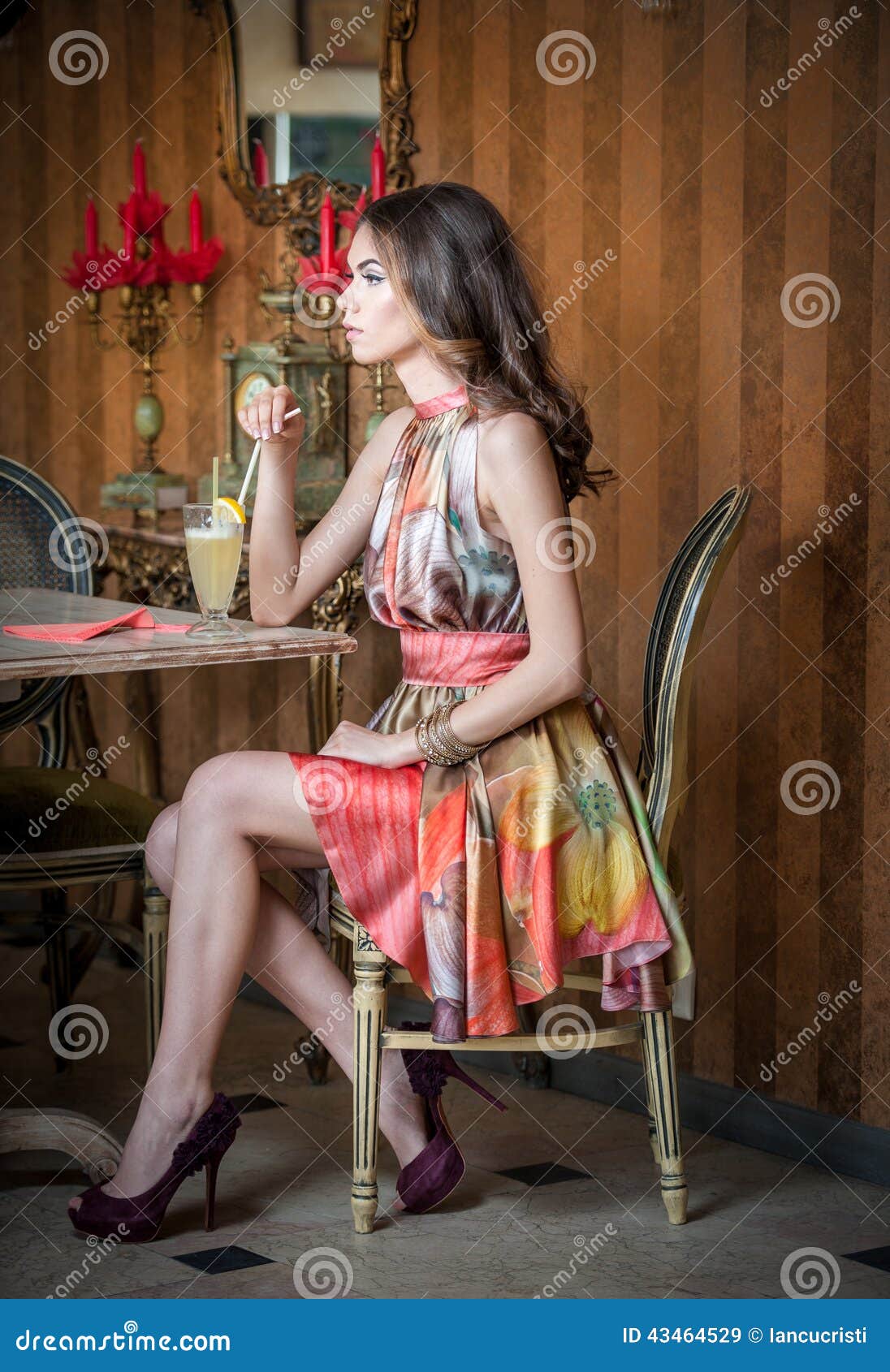 Fashionable Attractive Woman In Multicolored Dress Sitting In