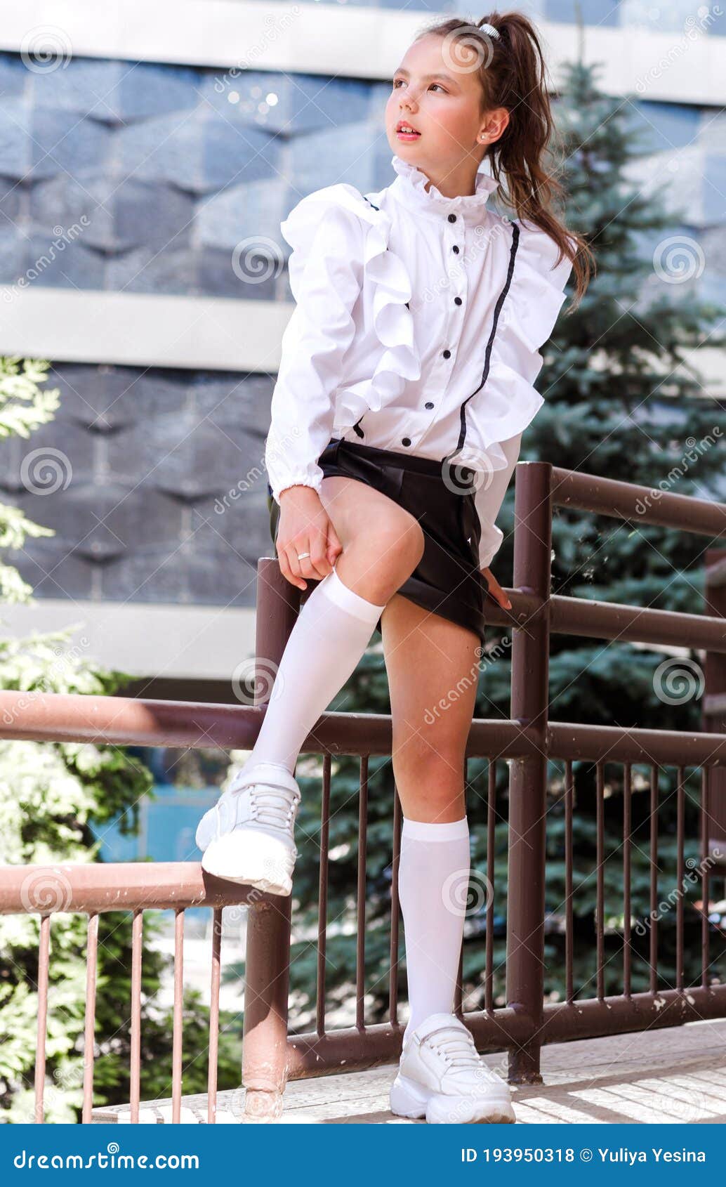 A Fashionable Schoolgirl In A White Blouse Leather Shorts Socks And