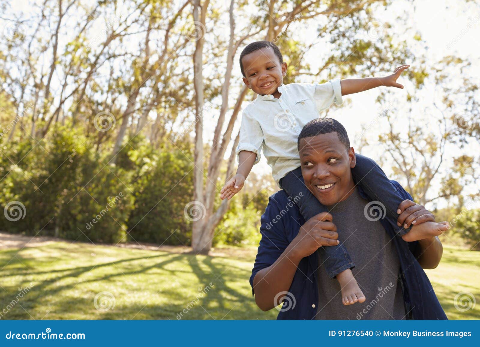 Father Carrying Son on Shoulders As they Walk in Park Stock Photo ...