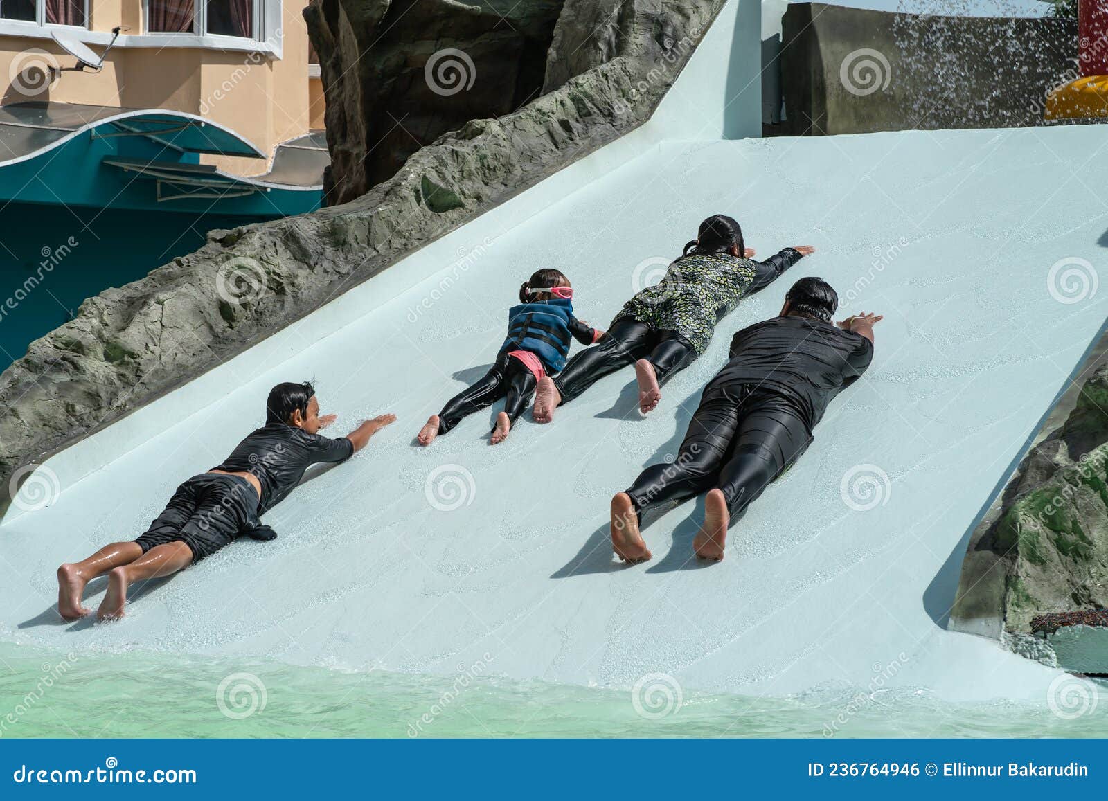 Father and Children Sliding into Pool after Going Down Water Slide ...