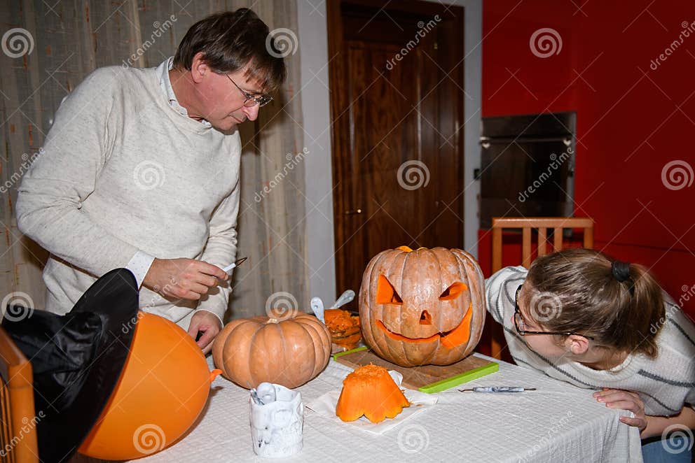 Father And Daughter Carving Pumpkin Jack O Lanterns On Halloween Party